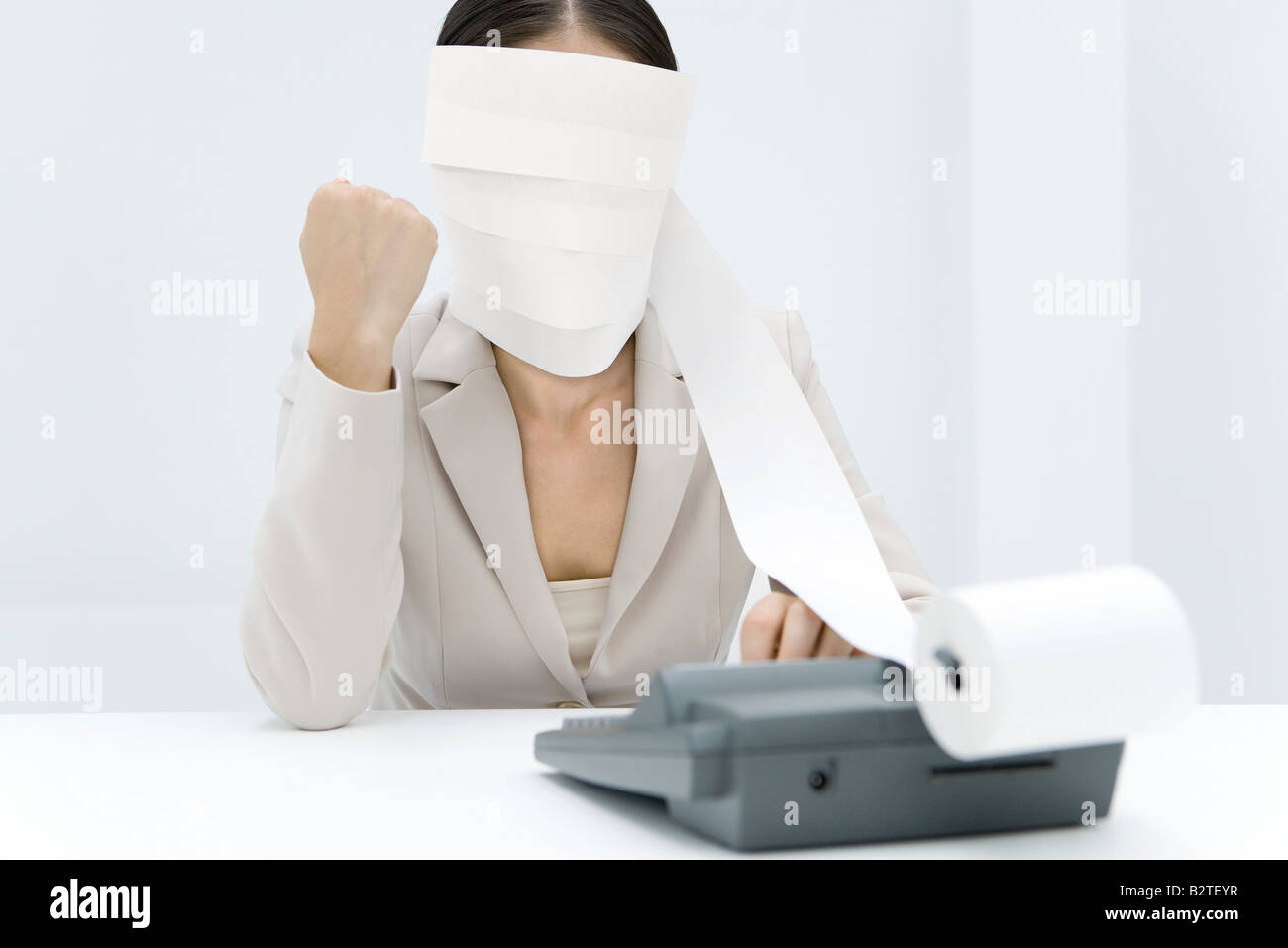Woman sitting at desk, tape from an adding machine wrapped around her ...
