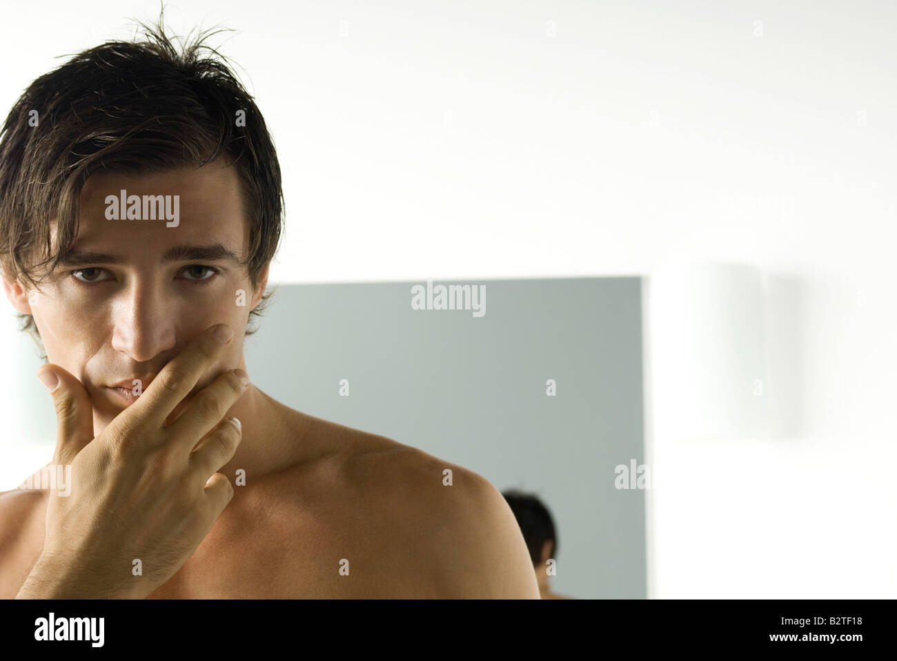 Bare-chested man touching his face, looking at camera, portrait Stock ...