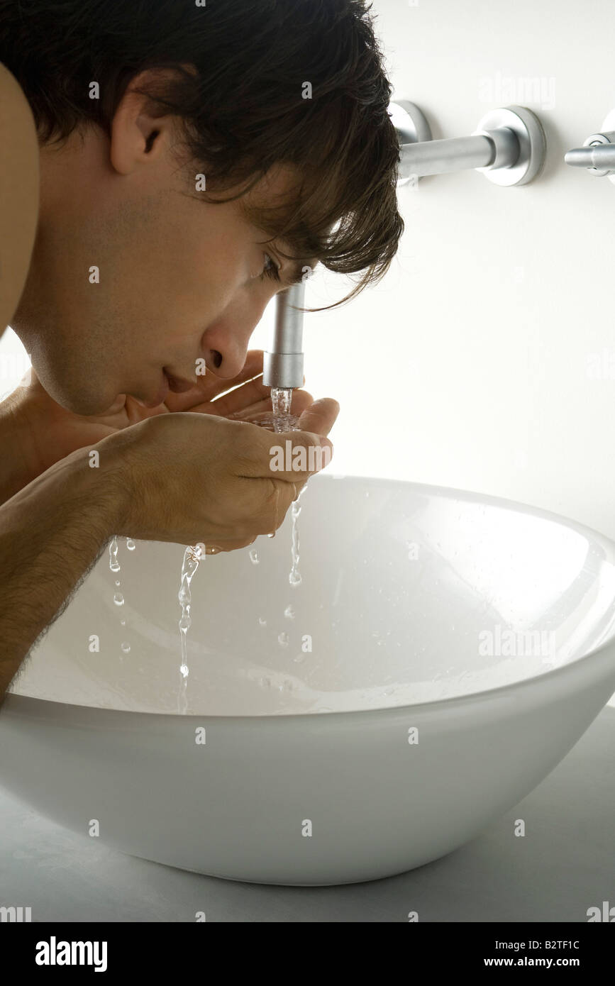 Man bending over sink, splashing water on face, cropped Stock Photo - Alamy