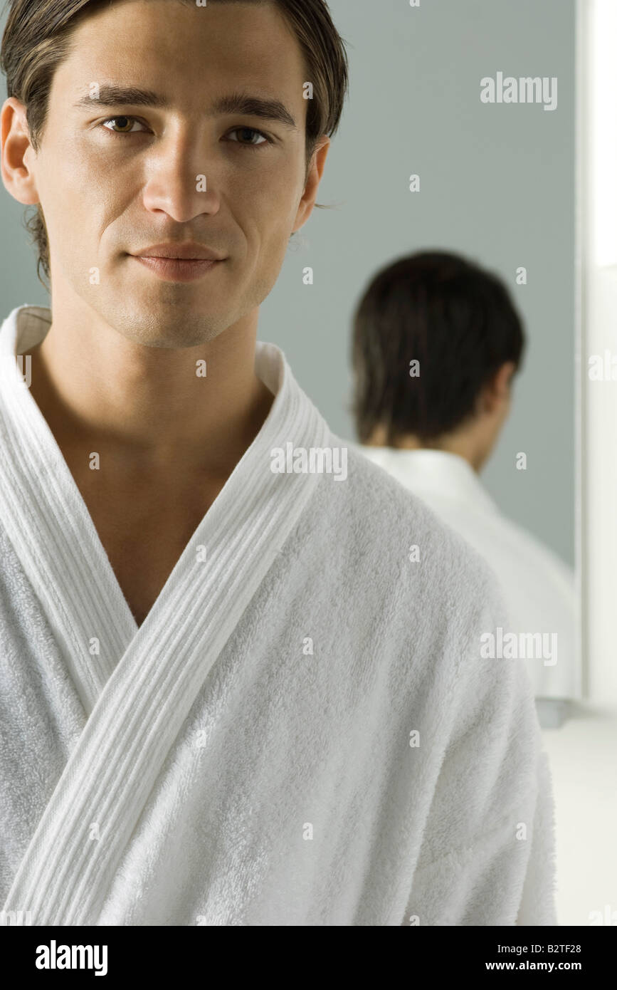 Man wearing bathrobe, smiling at camera, mirror in background Stock ...