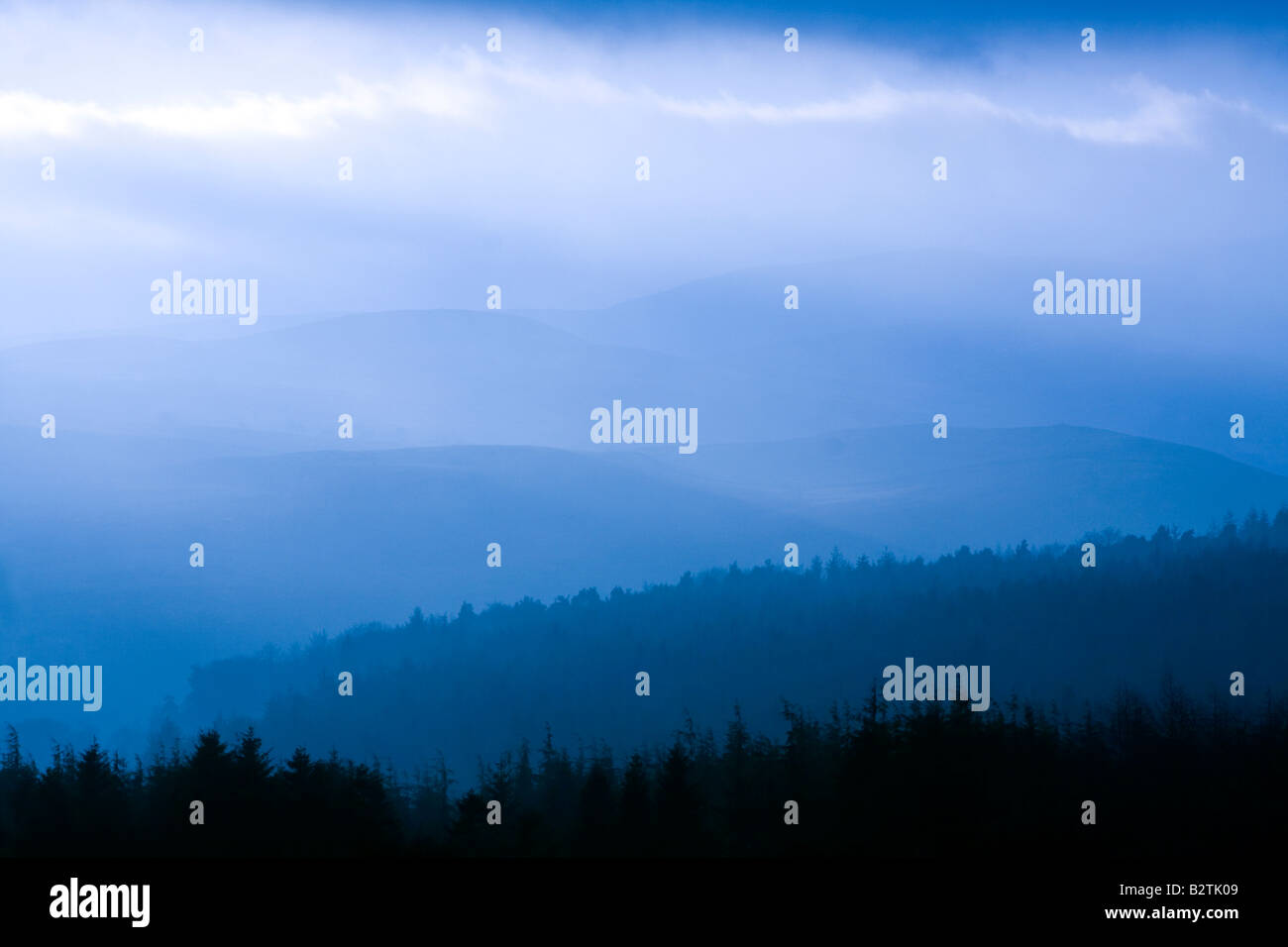 Blue hills covered in mist with streams of sunlight Stock Photo - Alamy