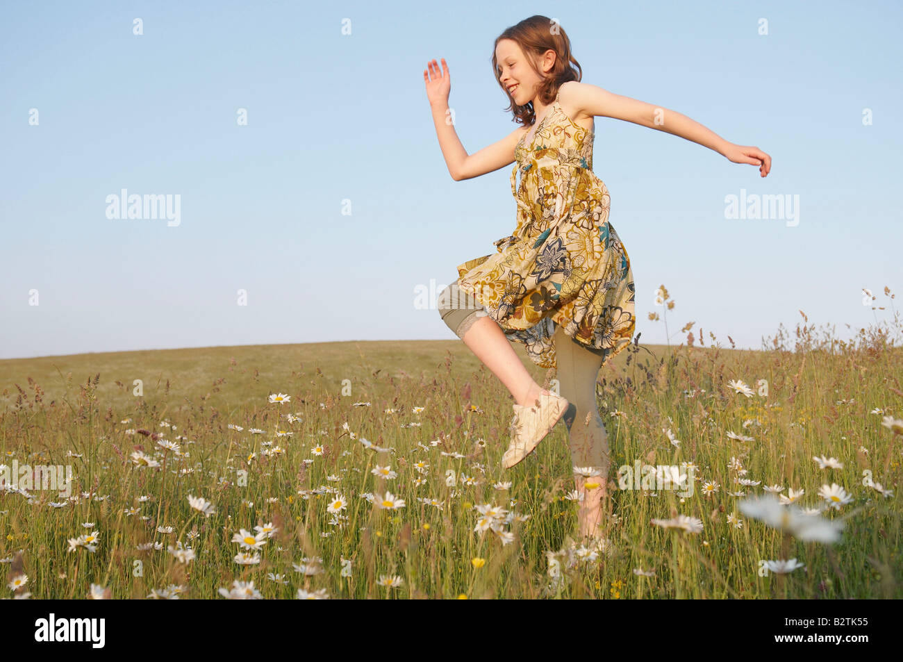Young girl skips in meadow Stock Photo - Alamy