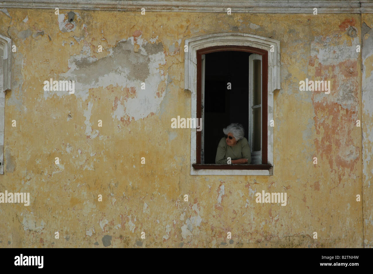 Old woman looking out of her window in a typical Portuguese village ...