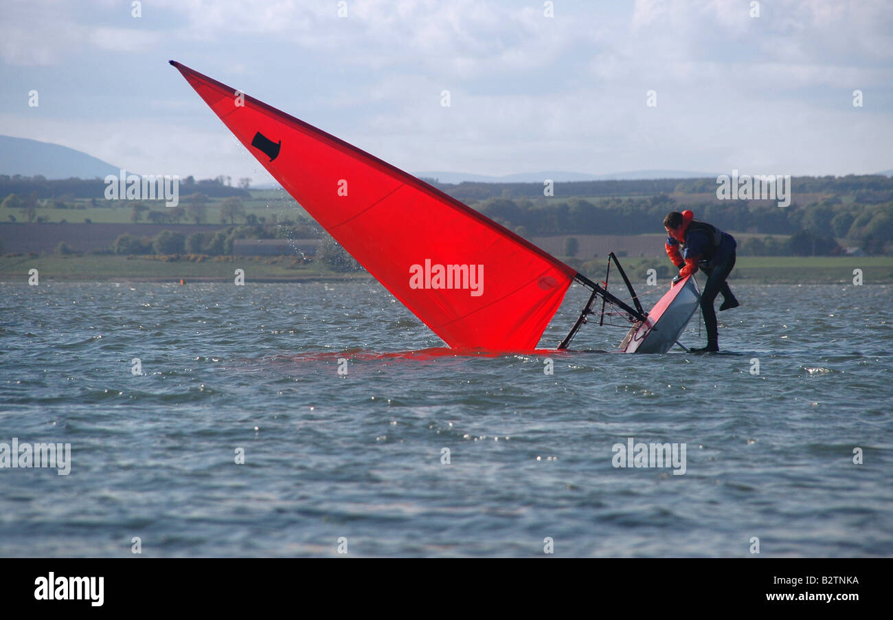 A young man struggles to keep his boat /dinghy upright as he turns ...