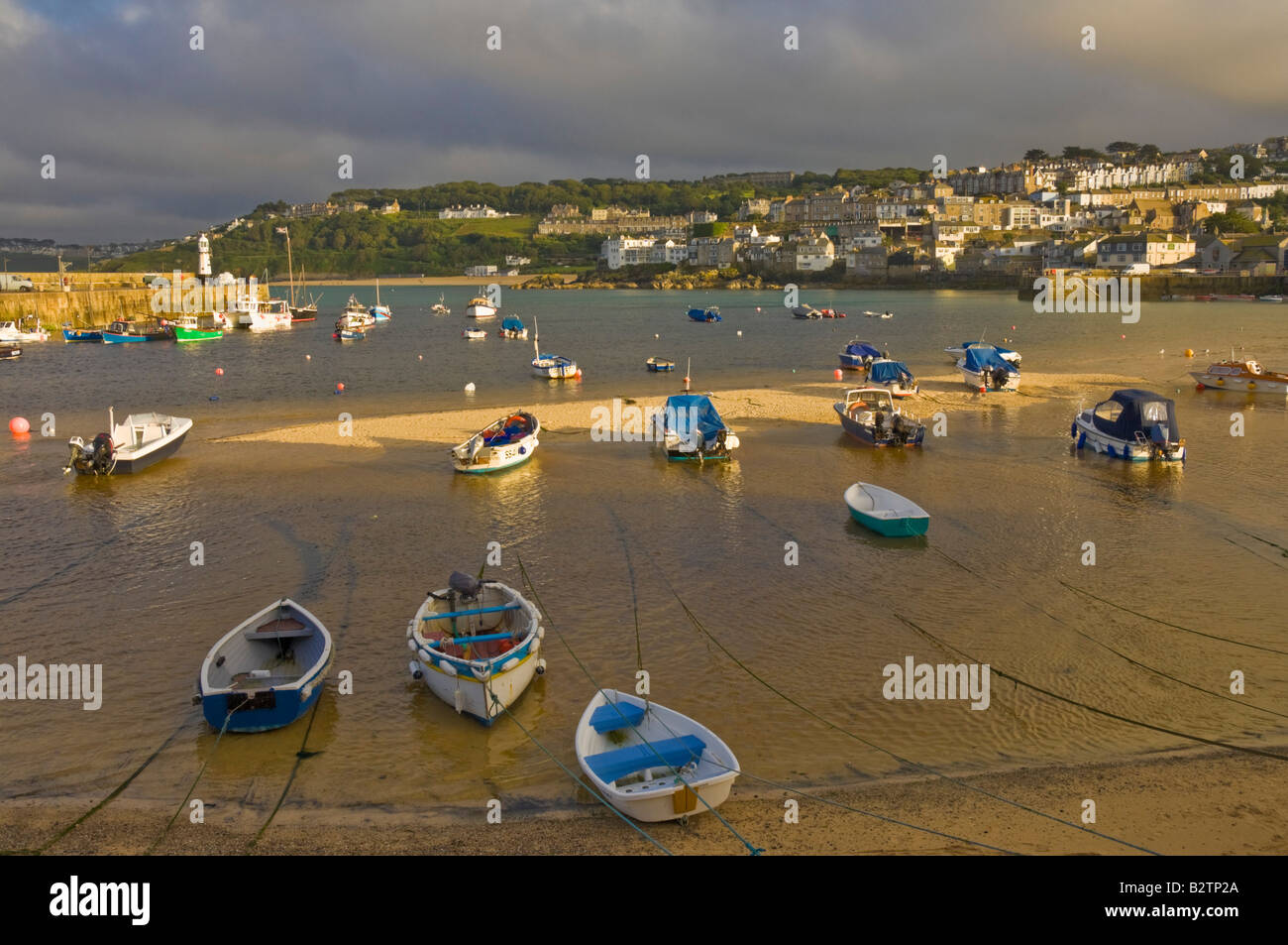 Fishing boats and stormy sunset in the harbour at low incoming tide St ...