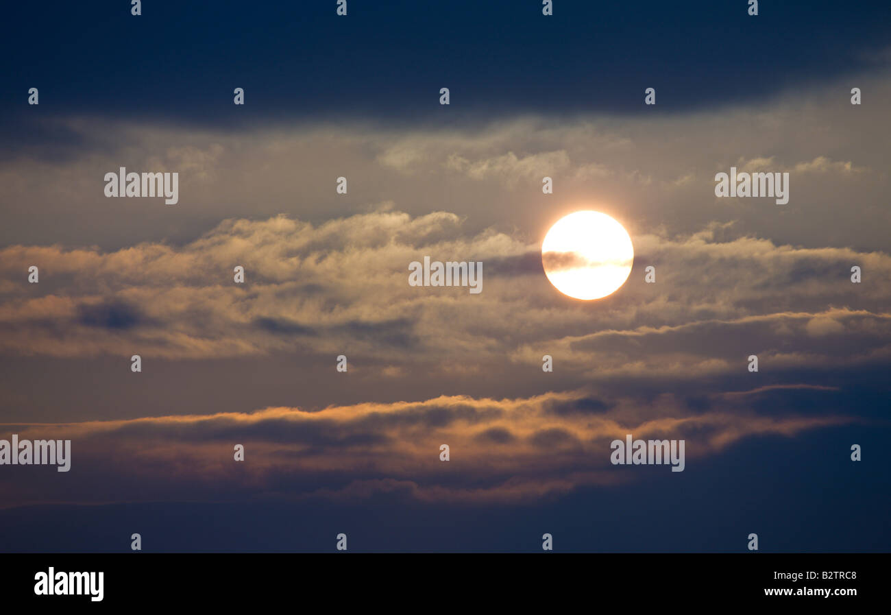 Early morning sun shining behind clouds Stock Photo - Alamy
