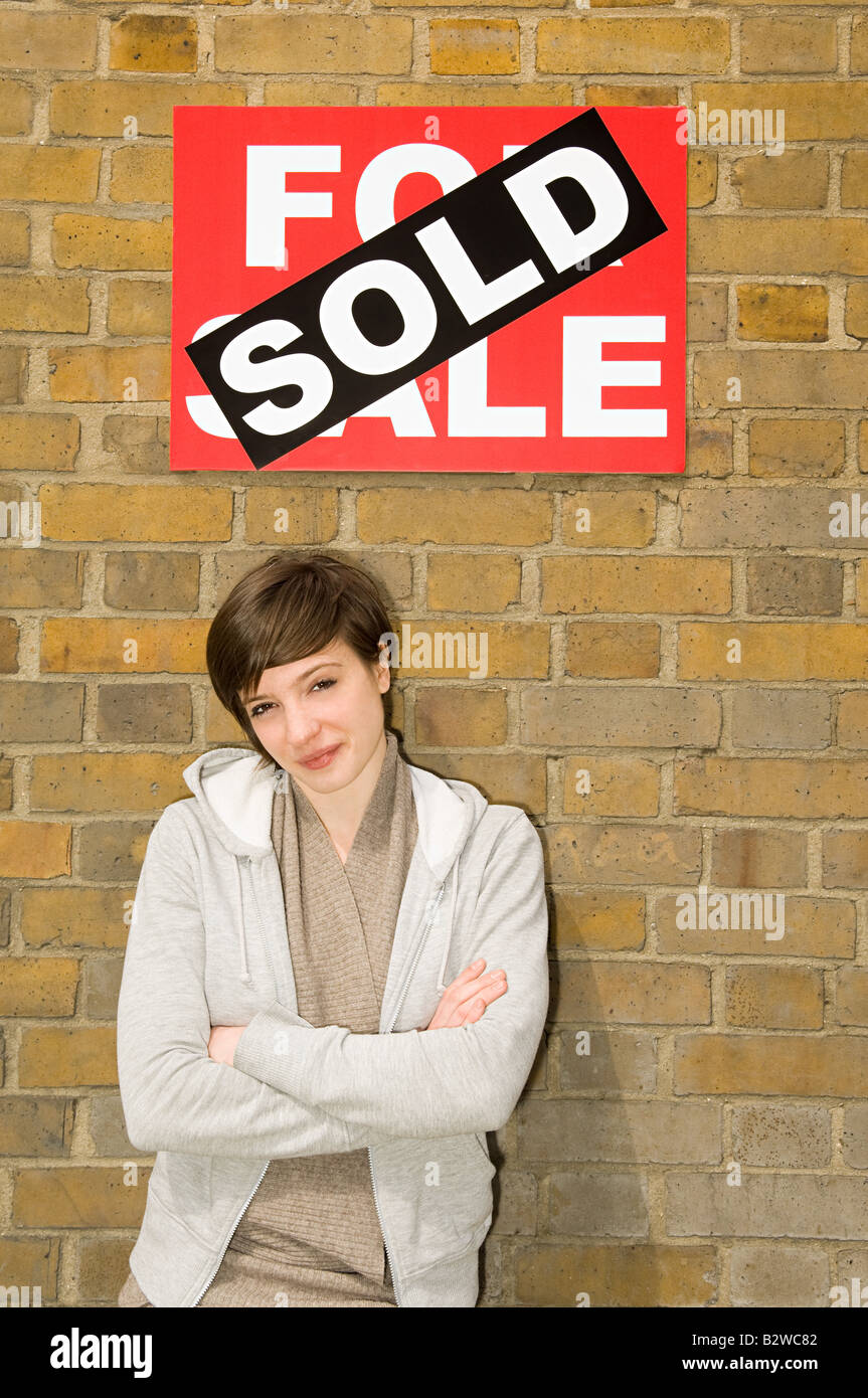Young woman and sold sign Stock Photo - Alamy