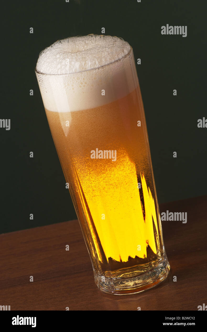 Freshly Poured Beer with Overflowing Foam in a Tall Glass Stock Photo ...