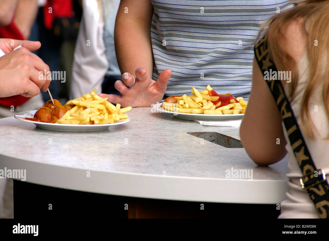 People eating German fast food, Currywurst) sausages and chips, Munich ...