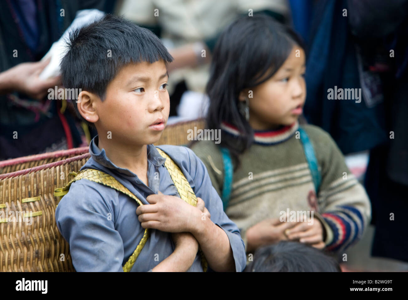Black Hmong hilltribe children with traditional shoulder baskets wait ...