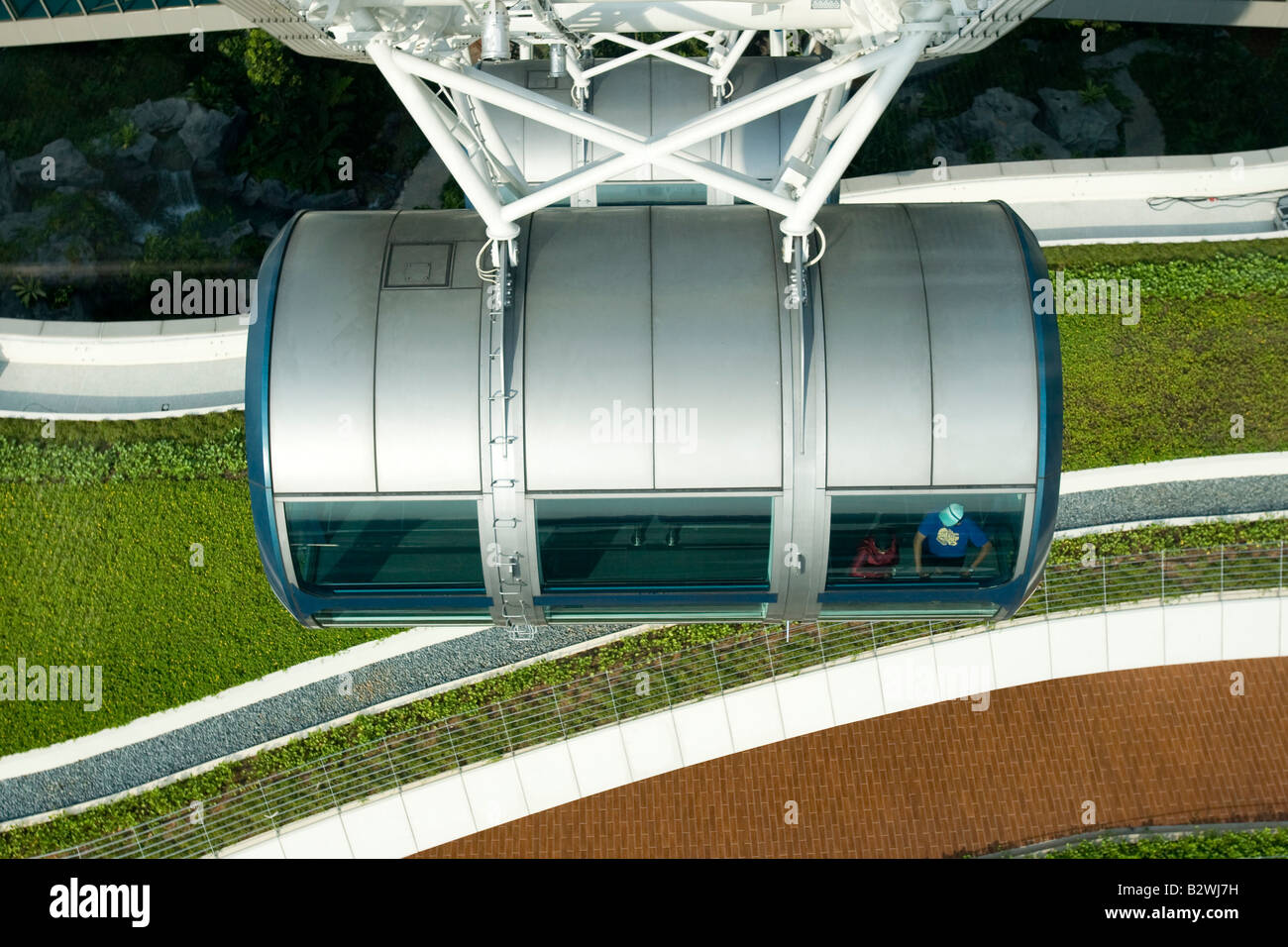 Two people watch view from cylindrical passenger capsule above grass ...