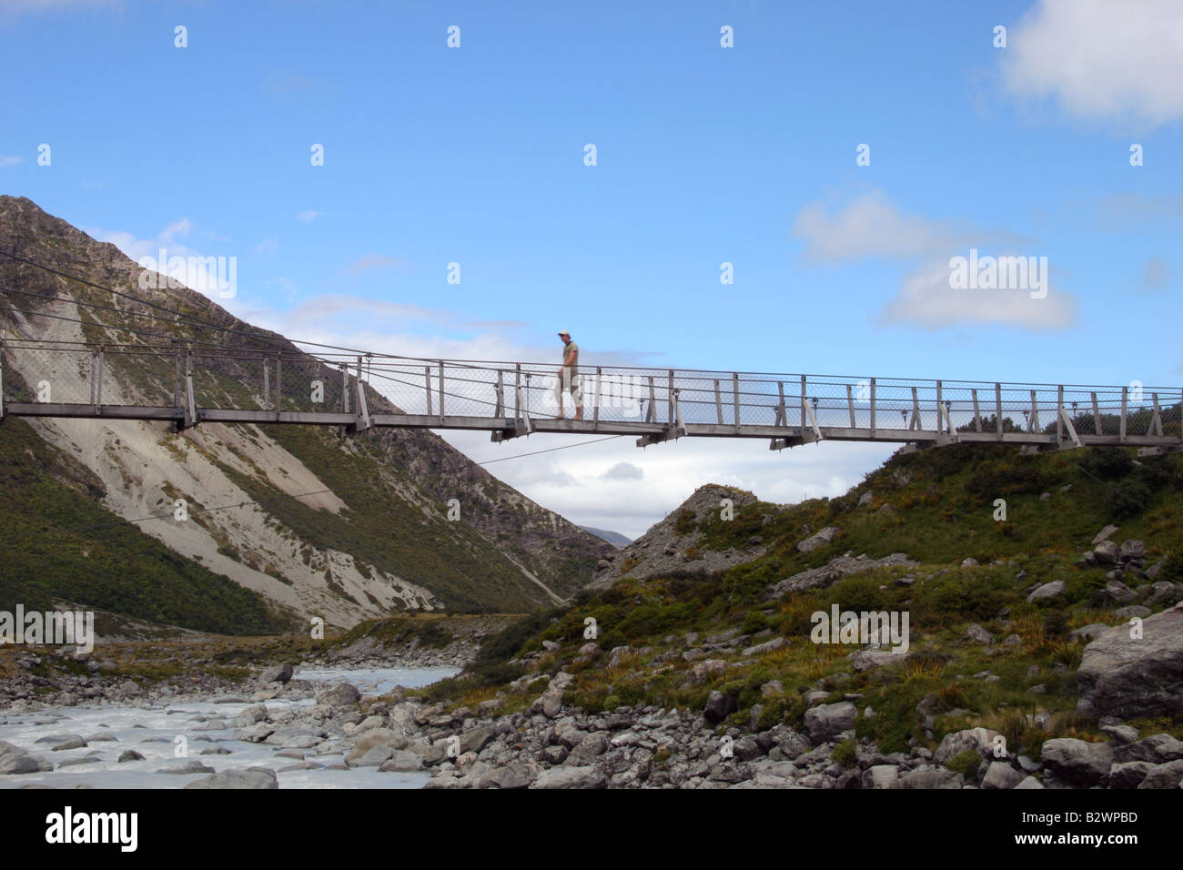 Backpacker crosses the Hooker River swing bridge in Mt Cook NP in the ...