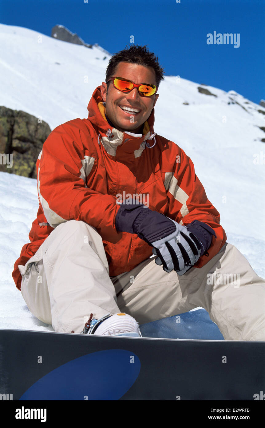 Snowboarder sitting on hill with board smiling (selective focus Stock ...