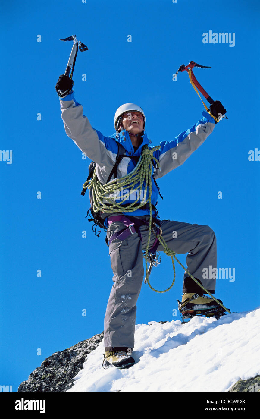 Mountain climber standing on snowy mountain victorious and smiling ...