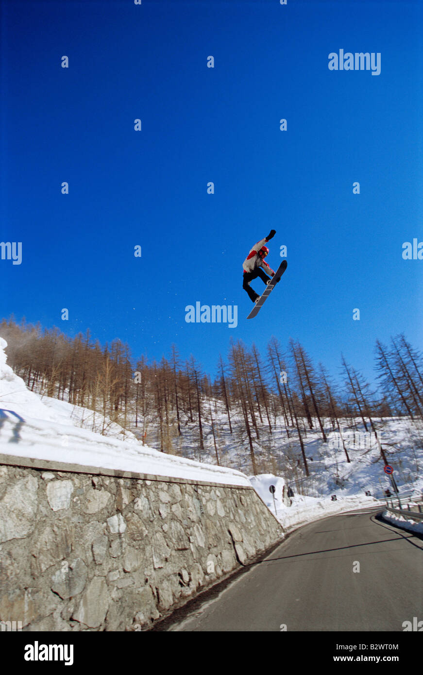 Snowboarder doing jump on snowy hill over a road (far away Stock Photo ...