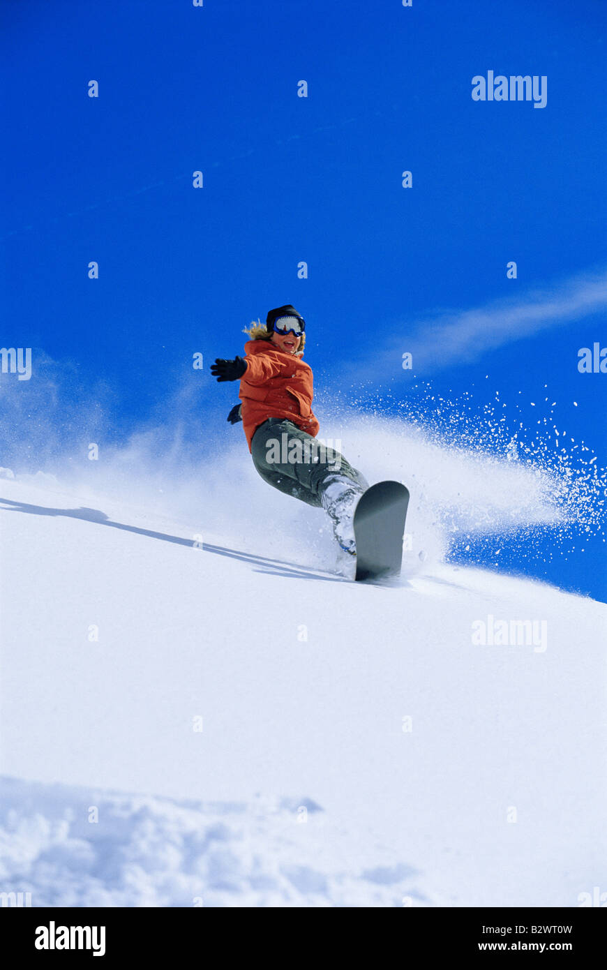 Snowboarder coming down snowy hill smiling Stock Photo - Alamy