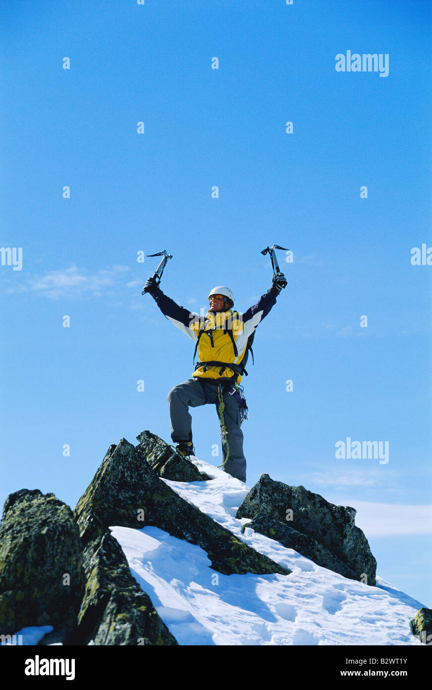 Mountain climber standing on snowy mountain victorious and smiling ...