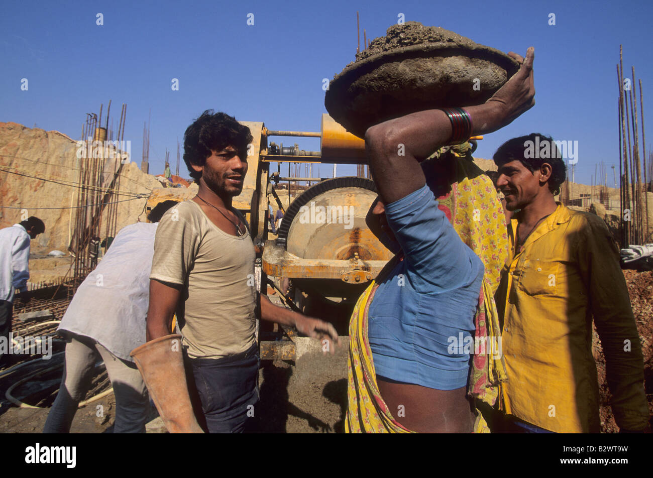 Indian construction workers, male and female, work on the foundation of ...