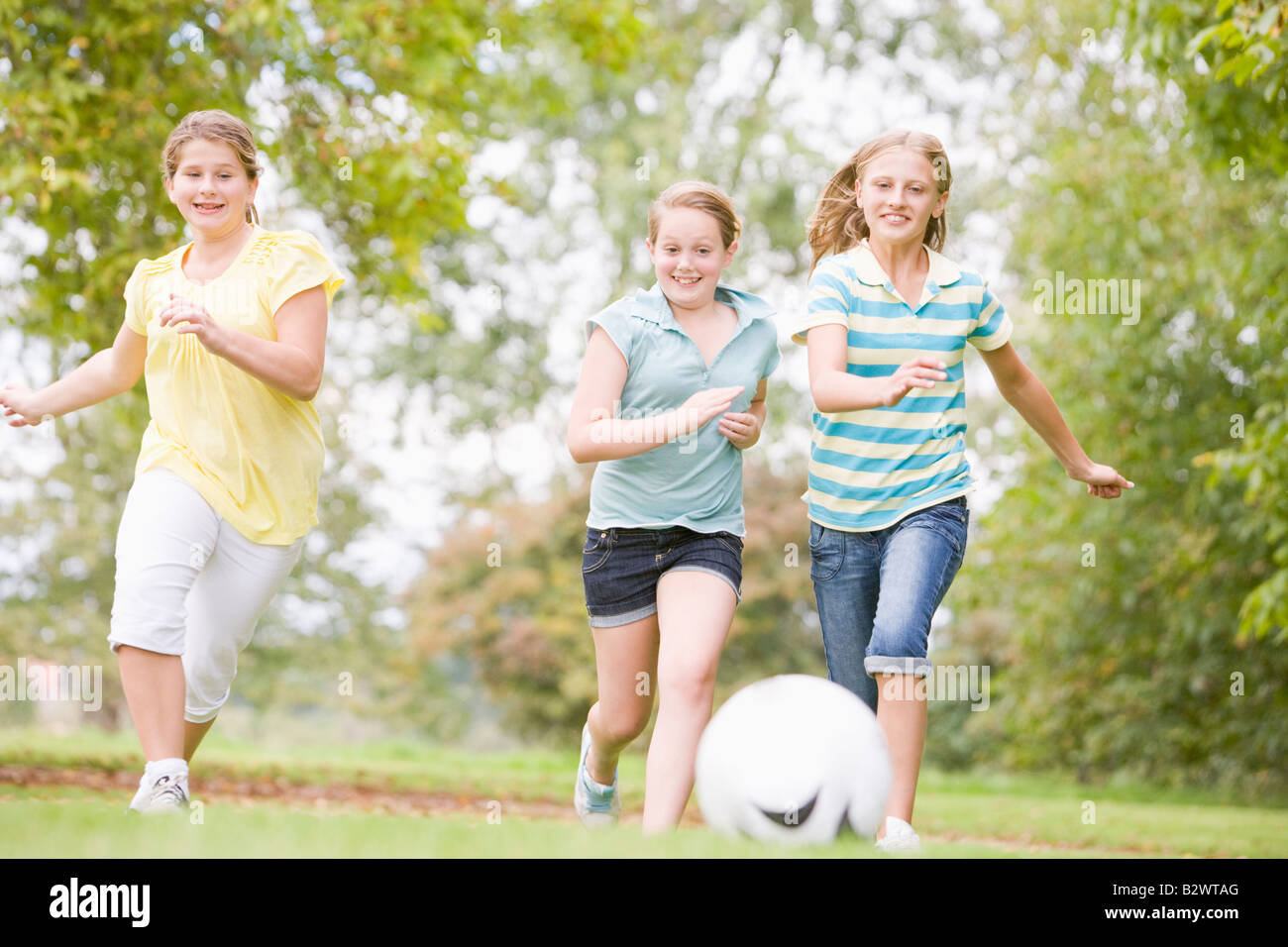 Three young girl friends playing soccer Stock Photo - Alamy