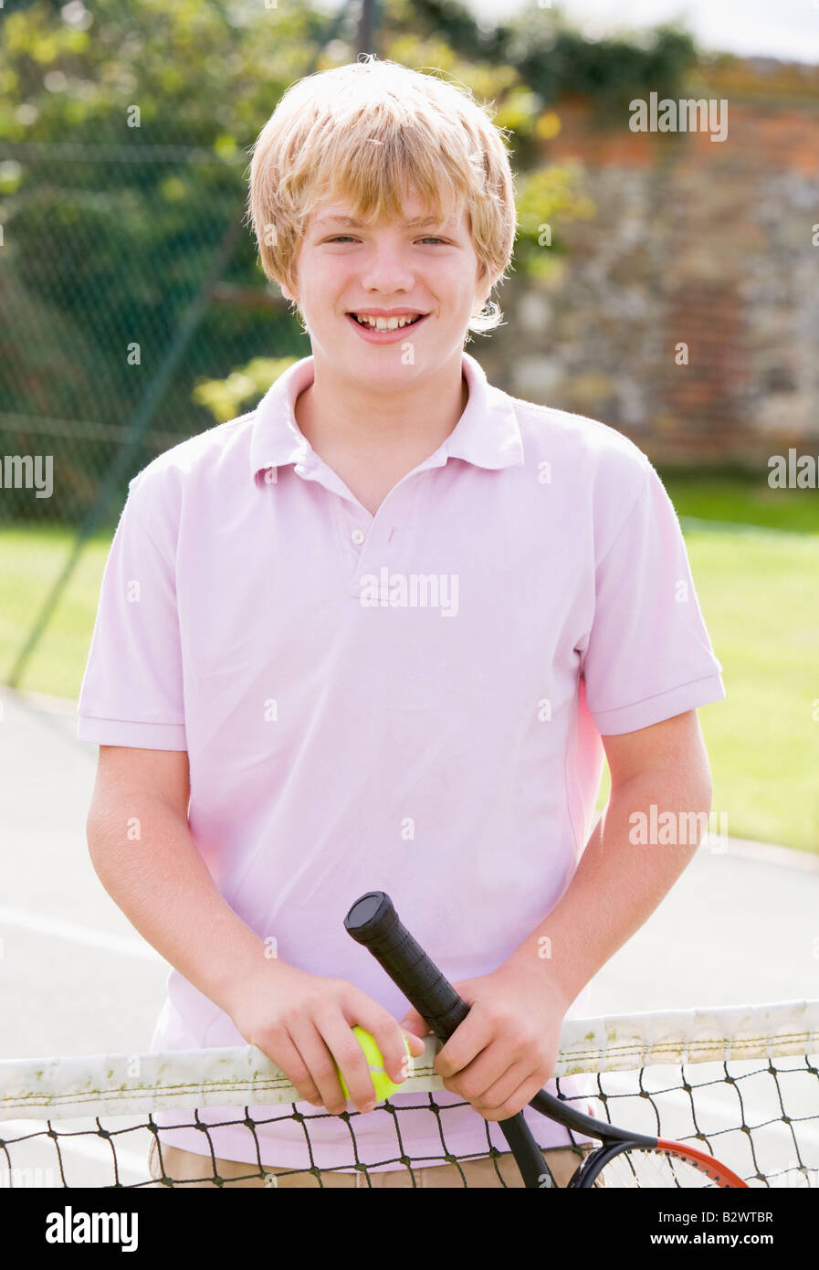 Young boy with racket on tennis court smiling Stock Photo - Alamy
