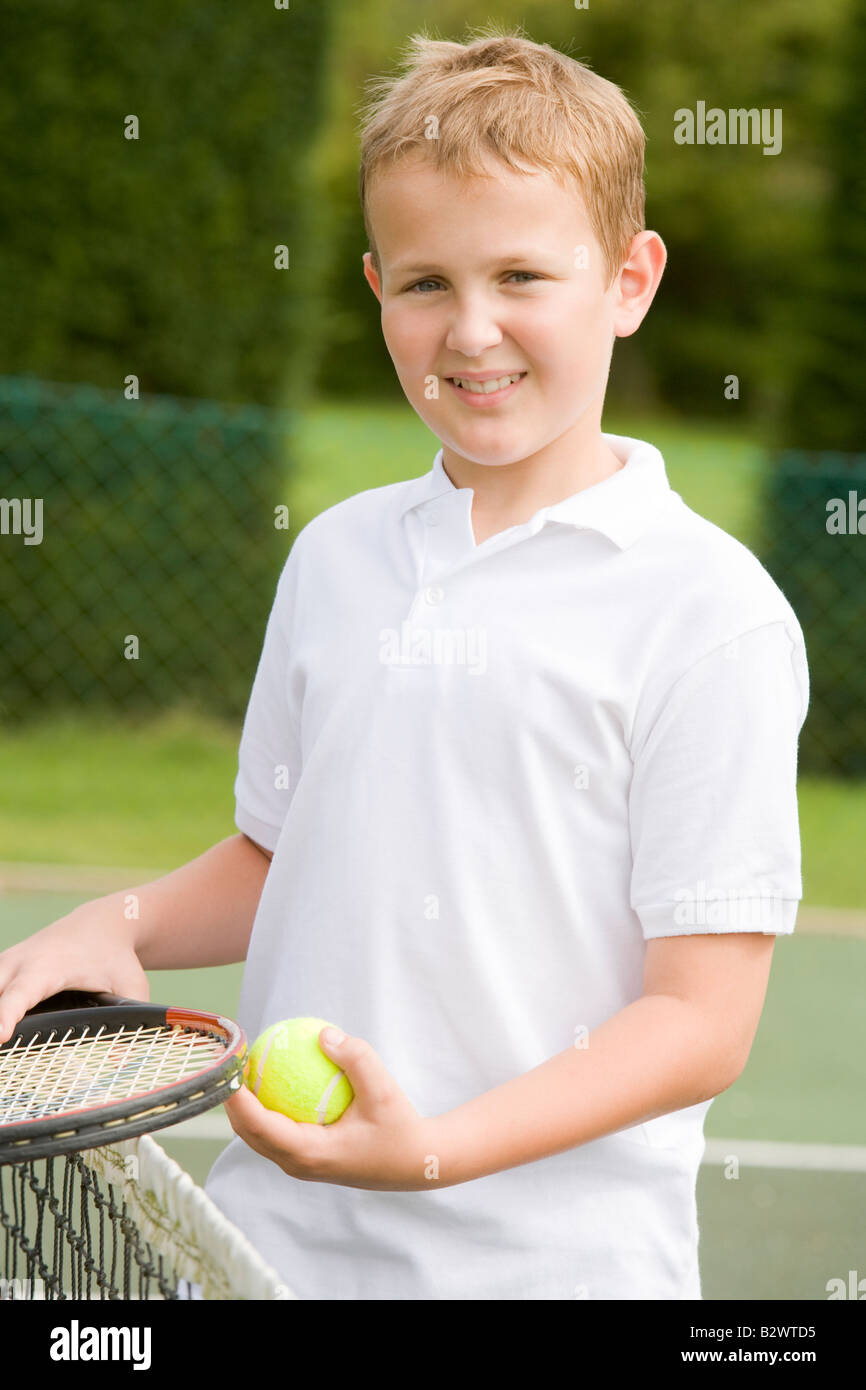 Young boy with racket on tennis court smiling Stock Photo - Alamy