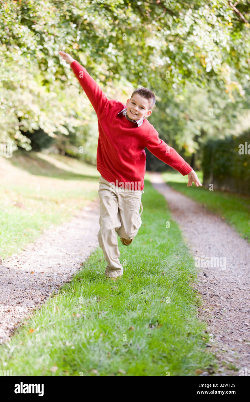 Young boy running on a path outdoors smiling Stock Photo - Alamy