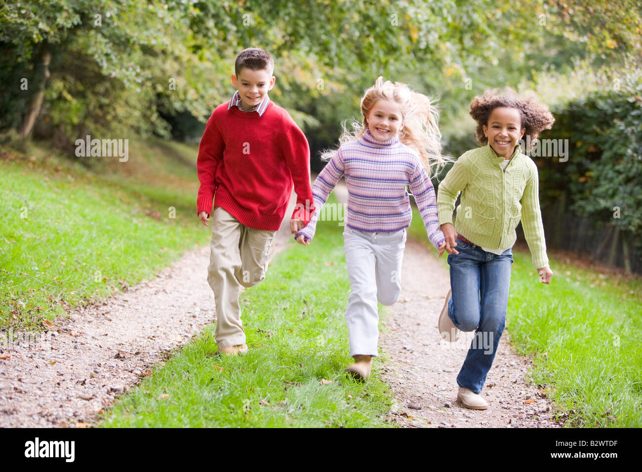 Three young friends running on a path outdoors smiling Stock Photo - Alamy