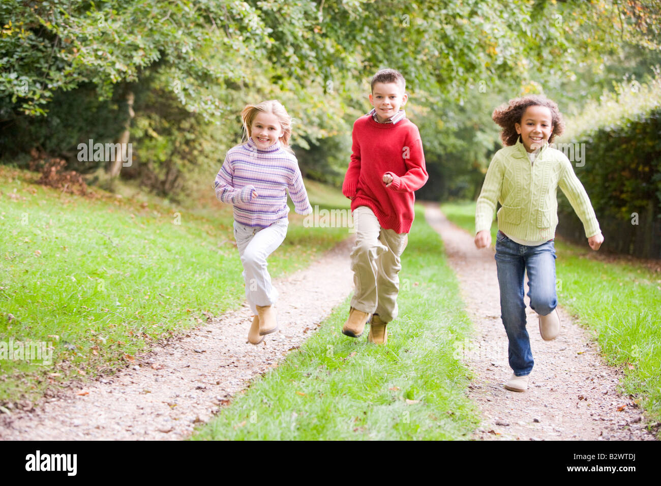 Three young friends running on a path outdoors smiling Stock Photo - Alamy