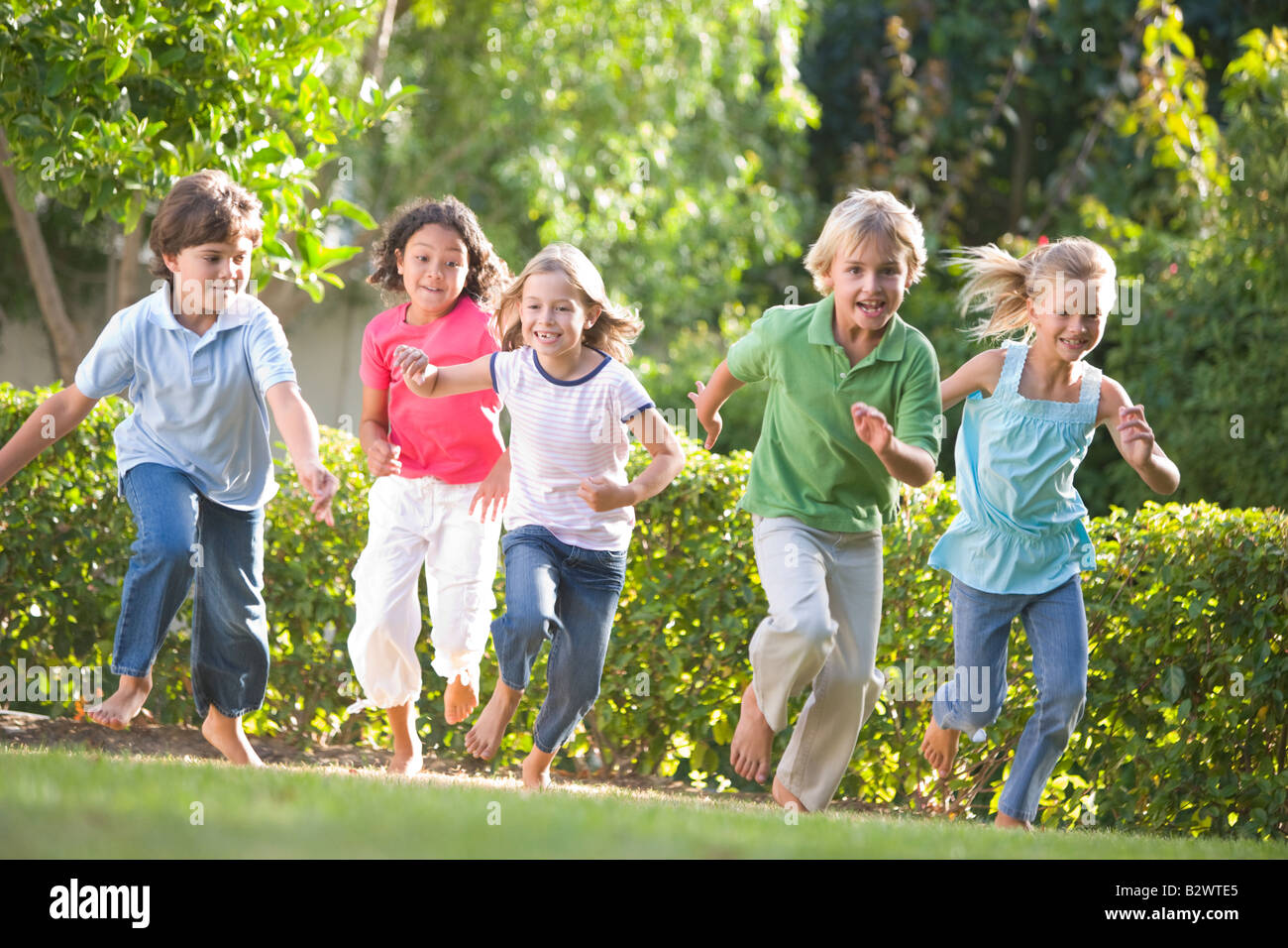 Five young friends running outdoors smiling Stock Photo - Alamy