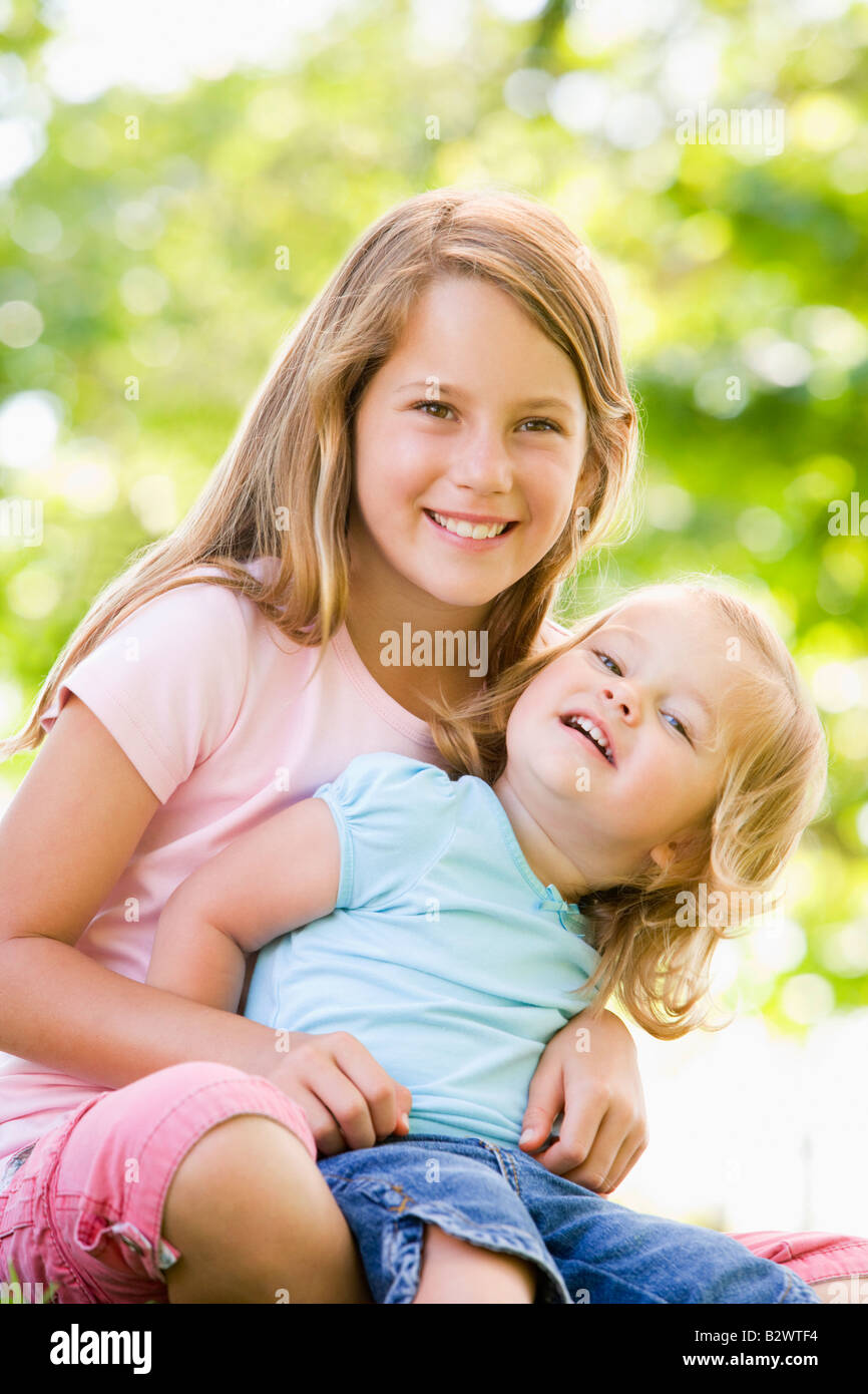 Two sisters sitting outdoors smiling Stock Photo - Alamy