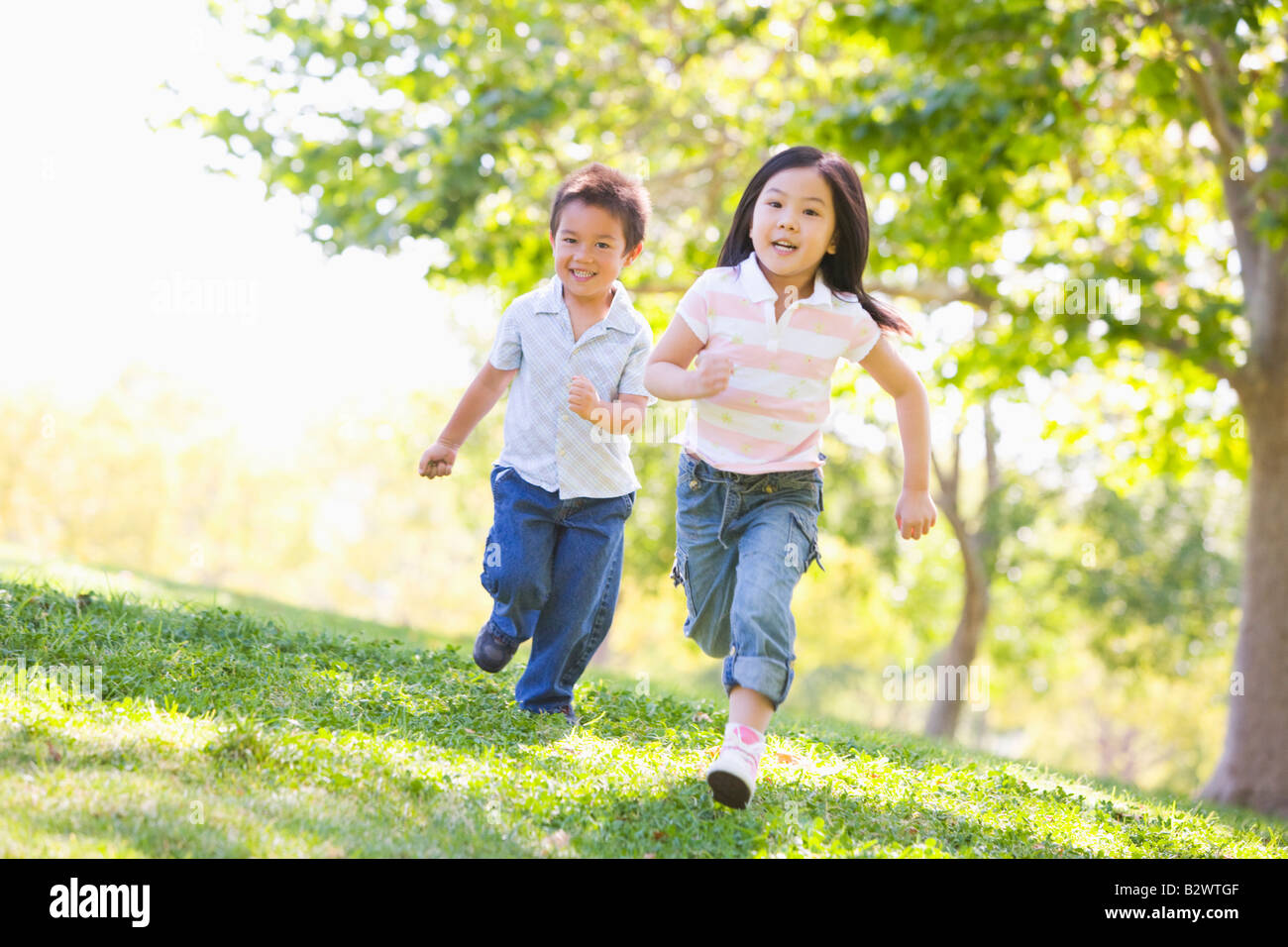 Brother and sister running outdoors smiling Stock Photo - Alamy