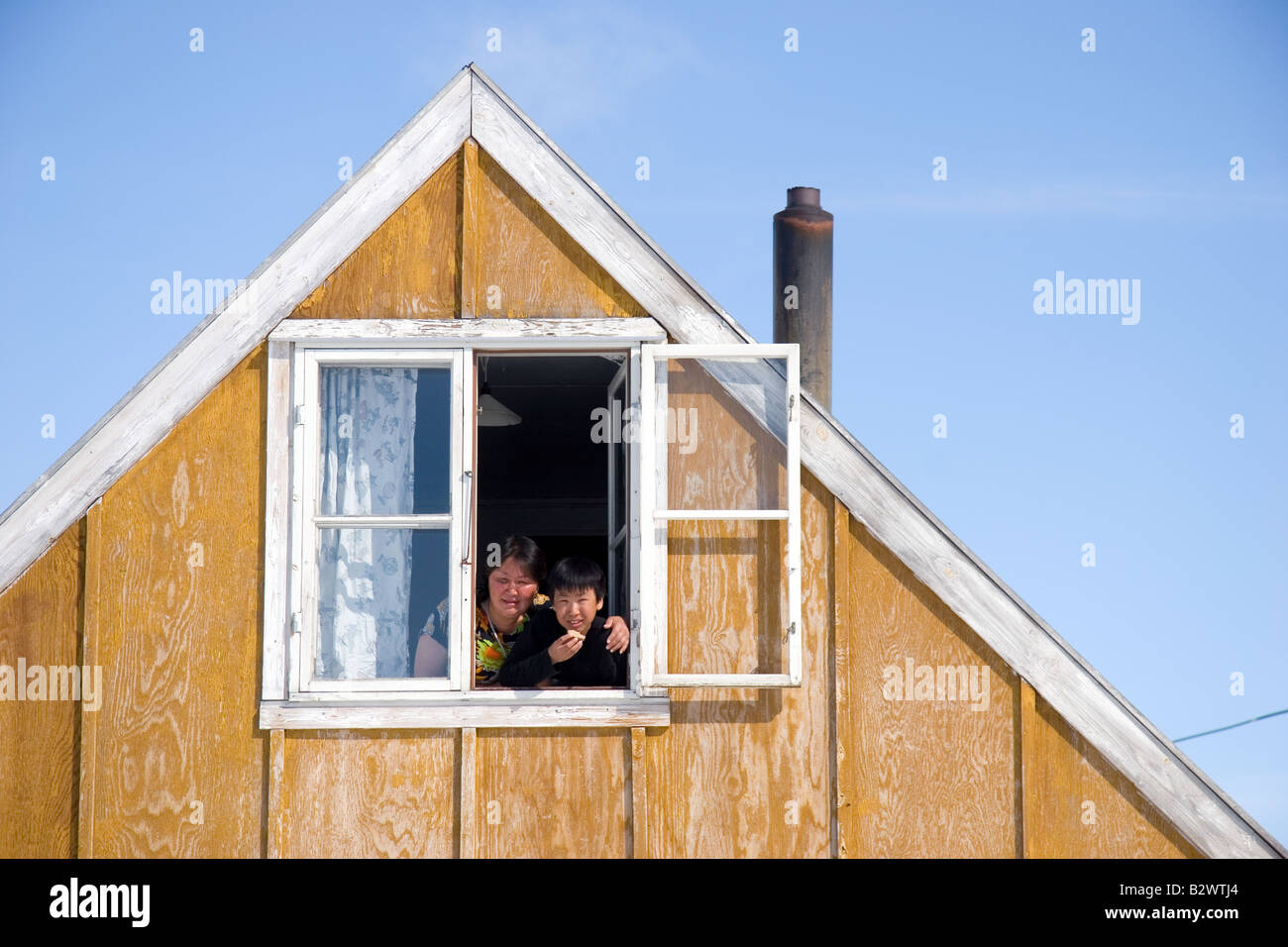 Inuit family at the window of their traditional colourful house in the ...