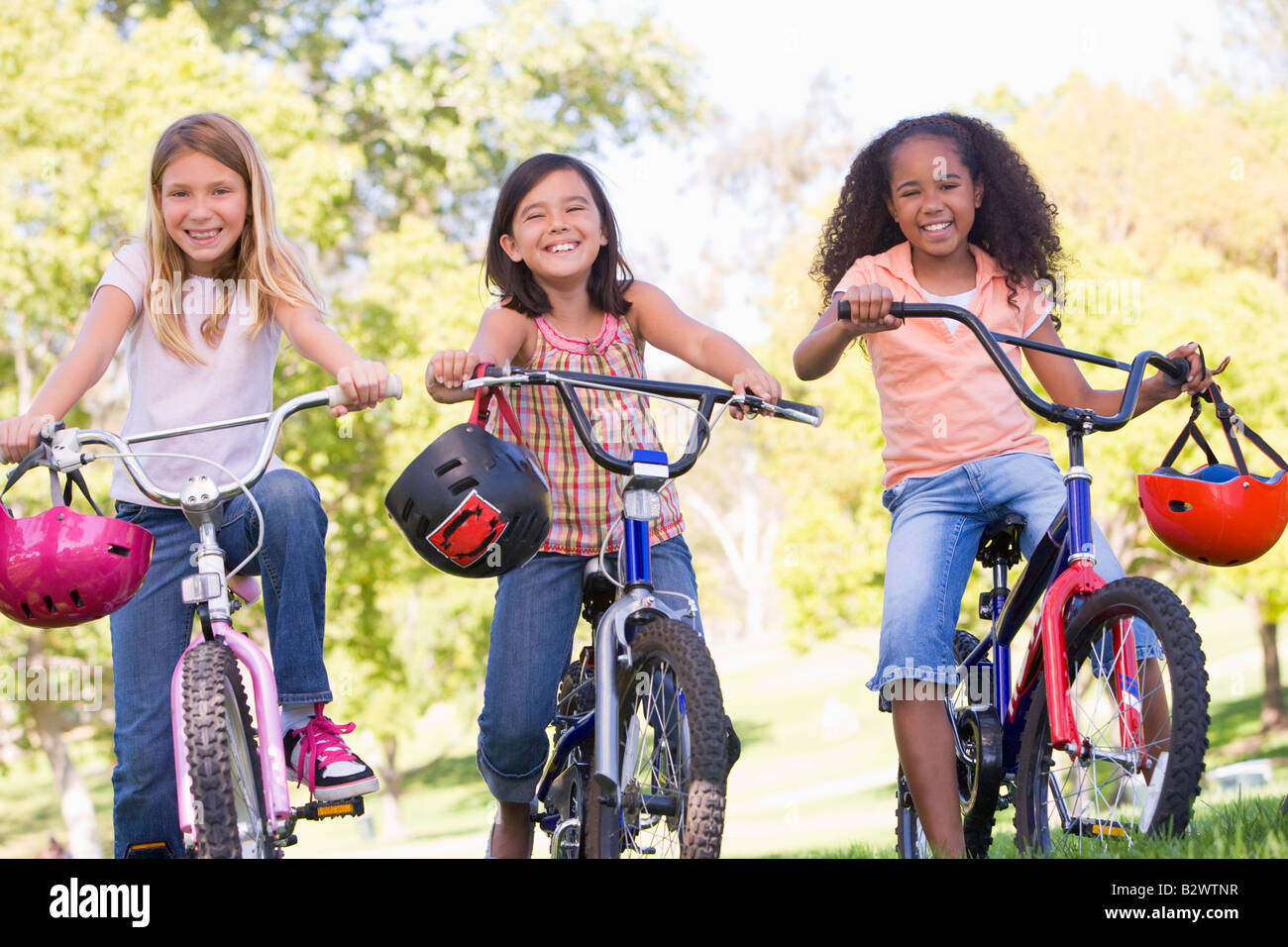 Three young girl friends outdoors on bicycles smiling Stock Photo - Alamy