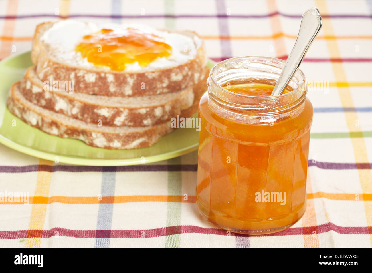 Toast with butter and peach jam glass jar in the green plate with soft ...