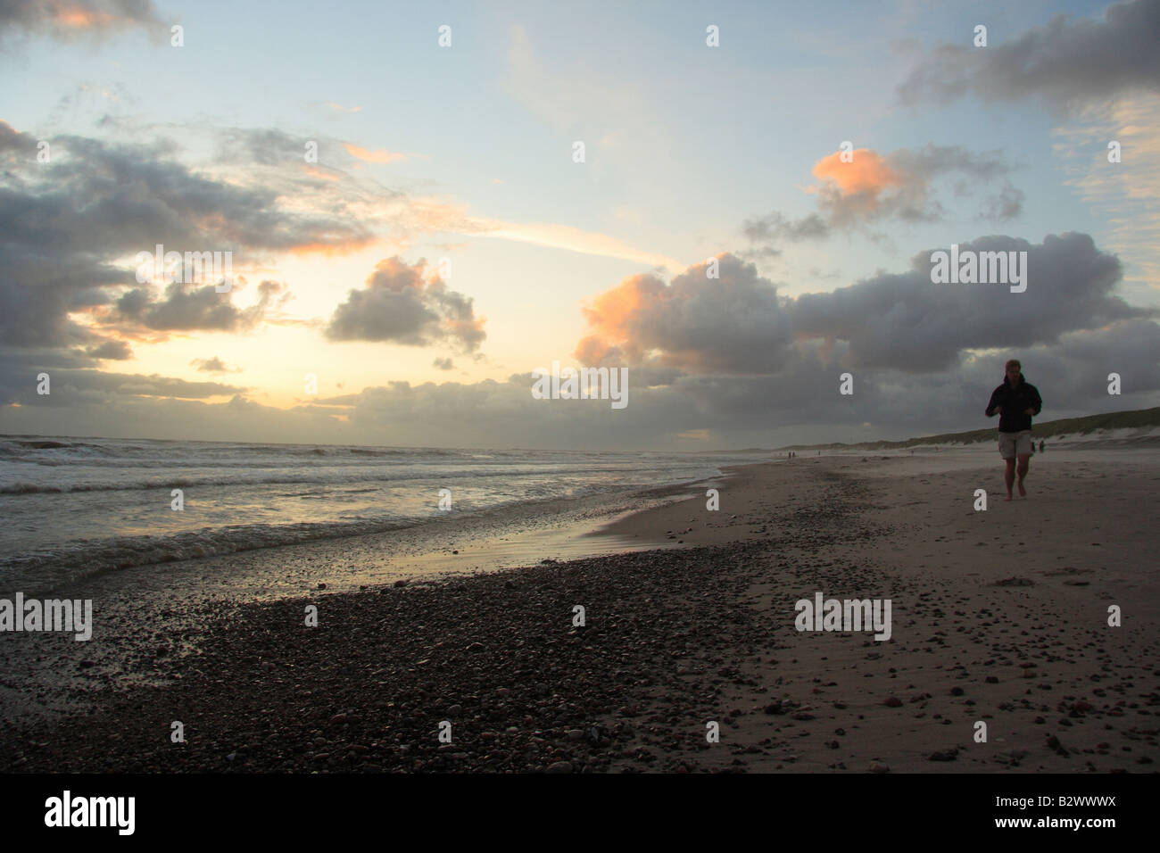 Man jogging along a beach at sunset Stock Photo - Alamy