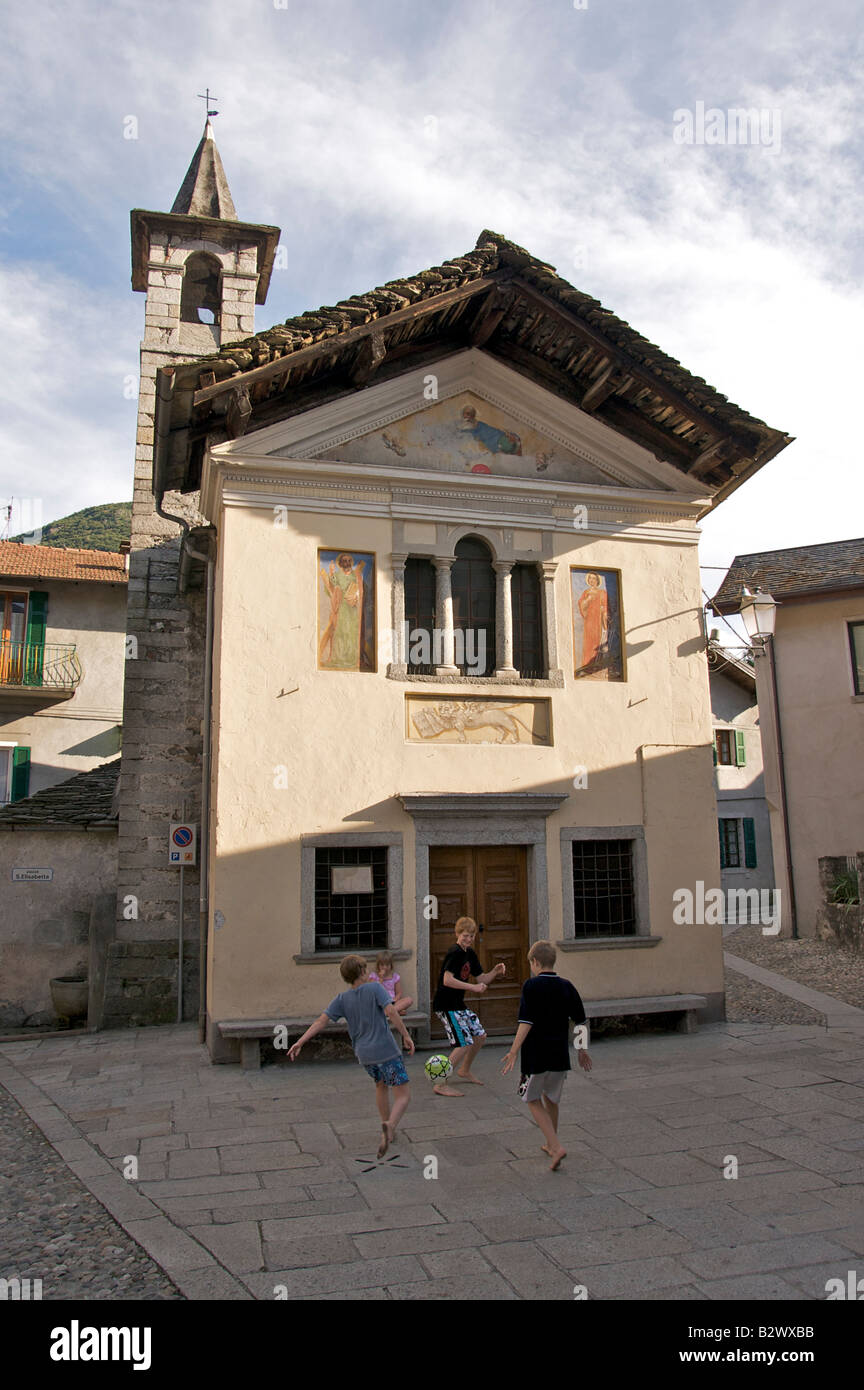 Kids playing soccer in front of an old church in Mergozzo, Piedmont ...