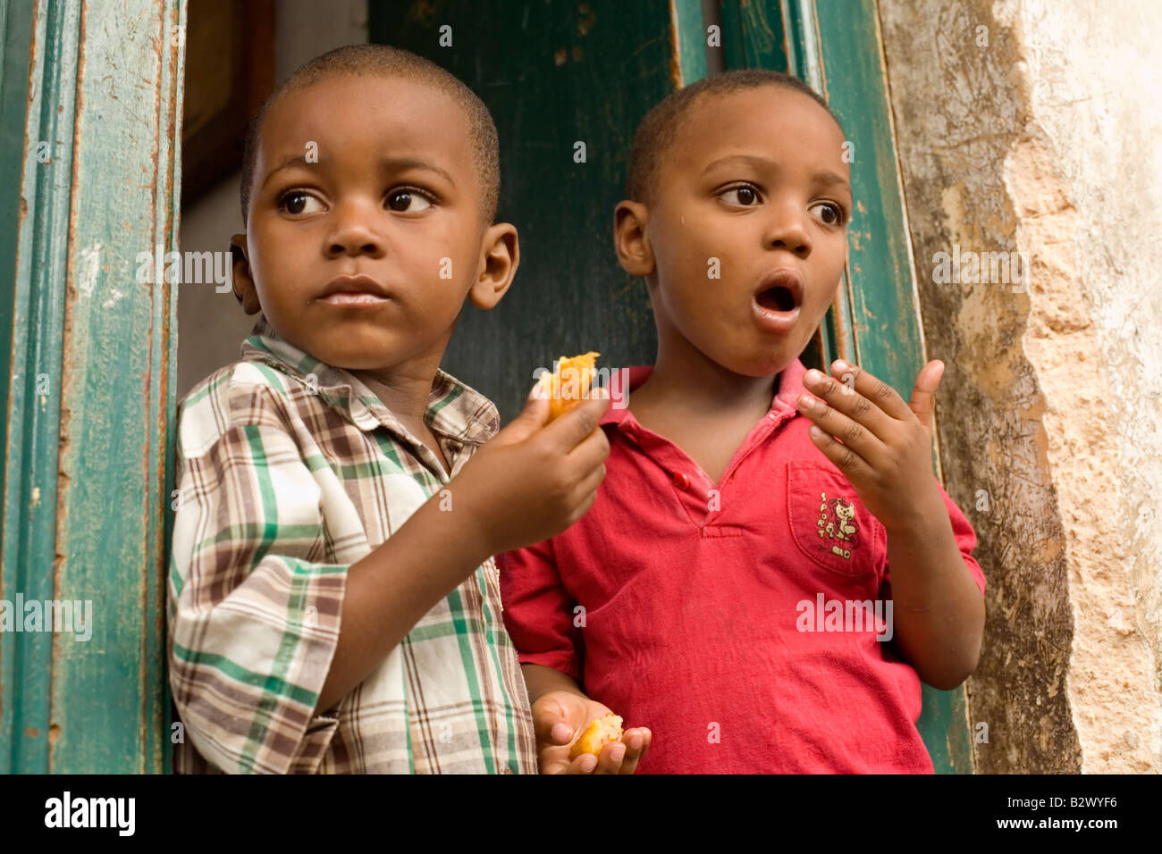Two children eating fruit in a doorway in Stone Town Zanzibar Stock ...