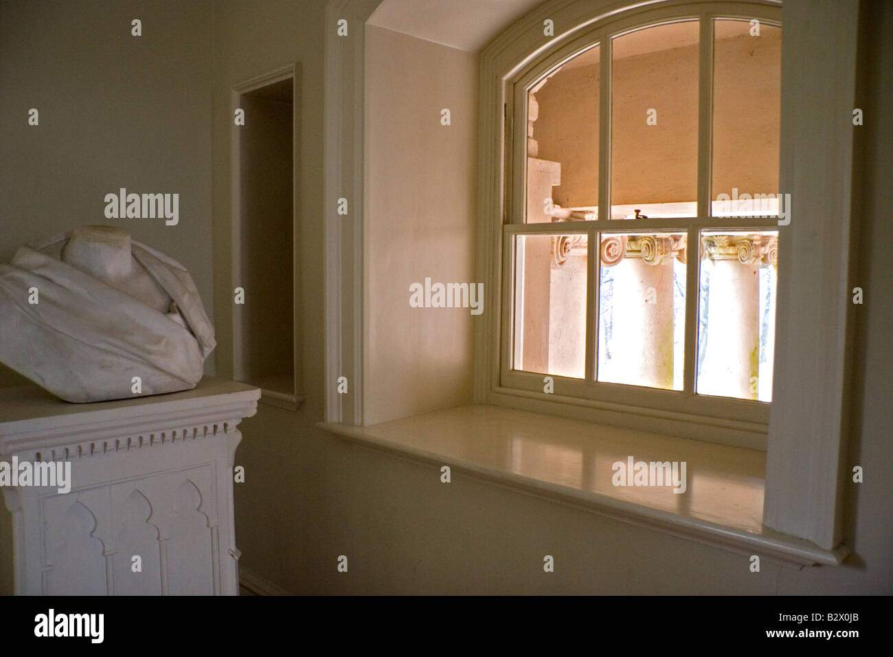 A headless bust on a plinth by a first floor window of a Georgian house ...