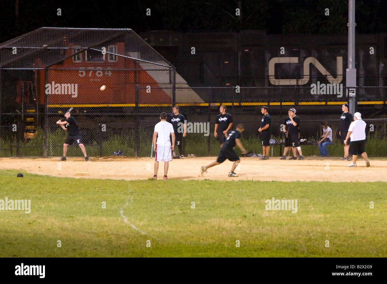 A Canadian National freight train moves past a softball game in ...