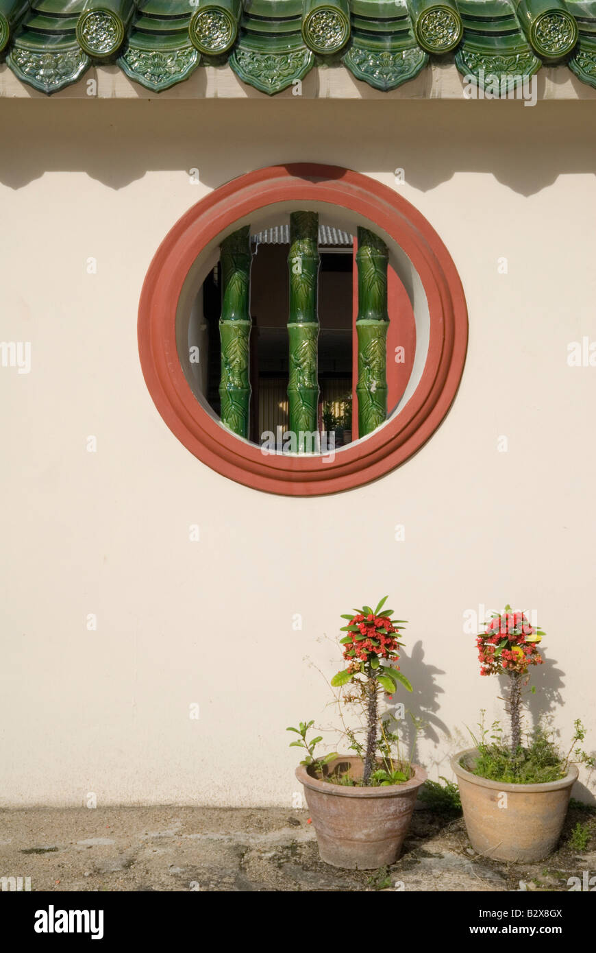 Courtyard pot plants and bamboo design round window in a wall at the ...