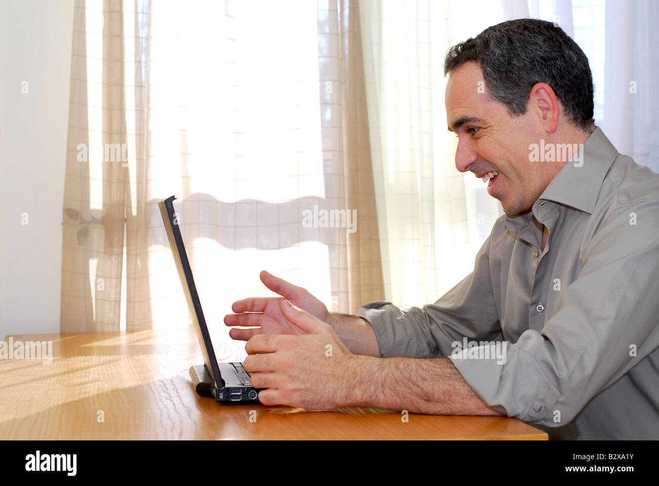 Man sitting at a desk and looking into his computer showing happiness ...