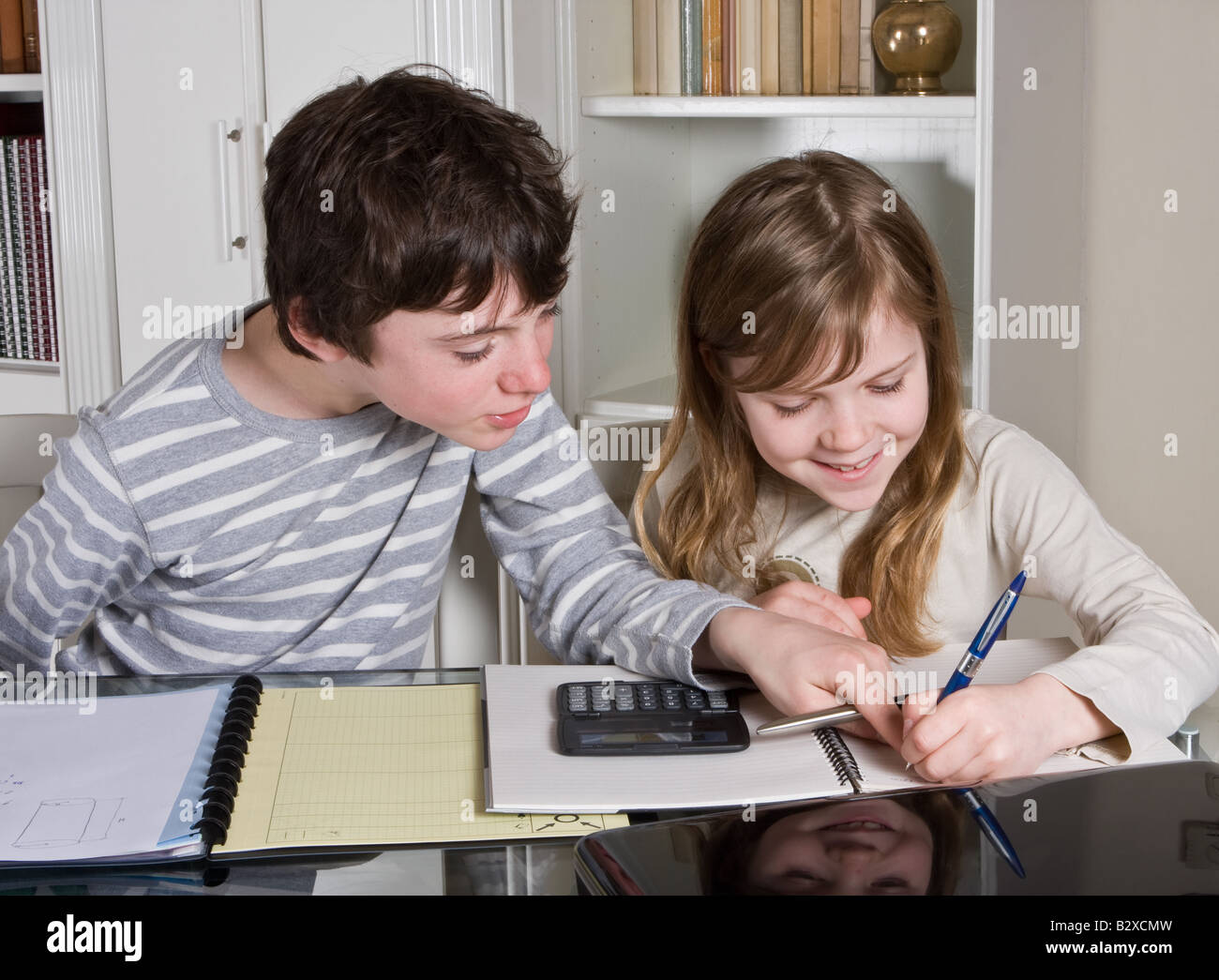 Young teenager boy helping his sister with her homework - back to ...