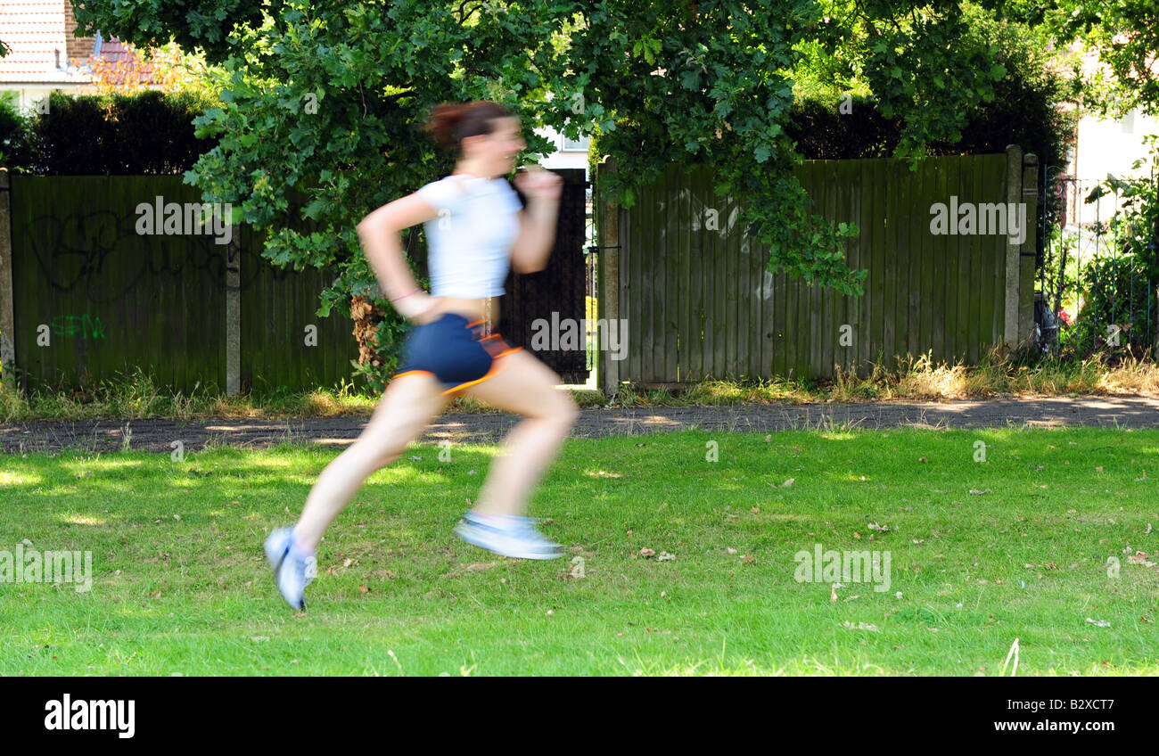 Woman jogging in the park on a hot summers day Step run running field ...