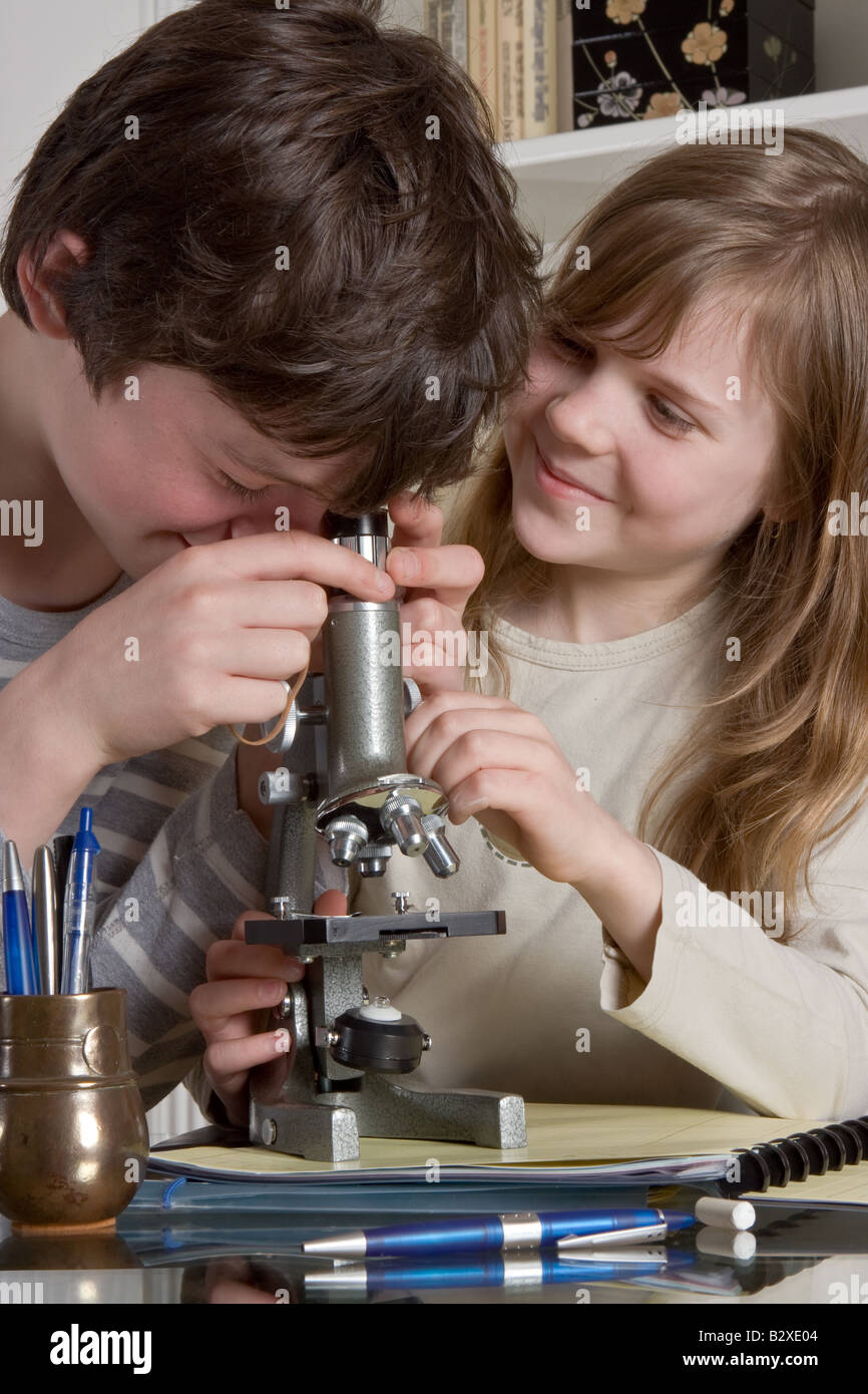 Two teenager kids working with a microscope - back to school Stock ...