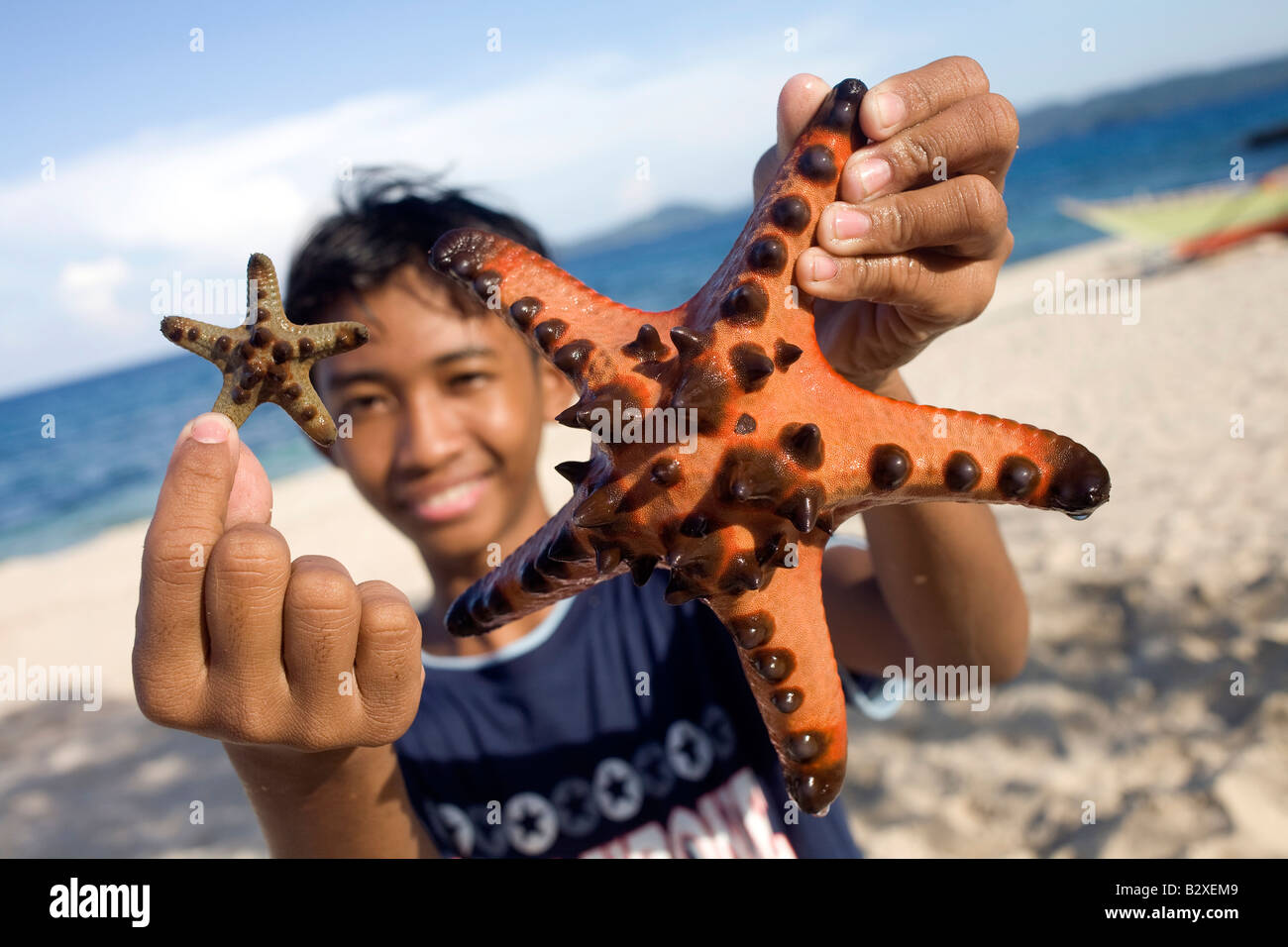 A Filipino boy holds a pair of sea stars at Buktot Beach near Mansalay ...