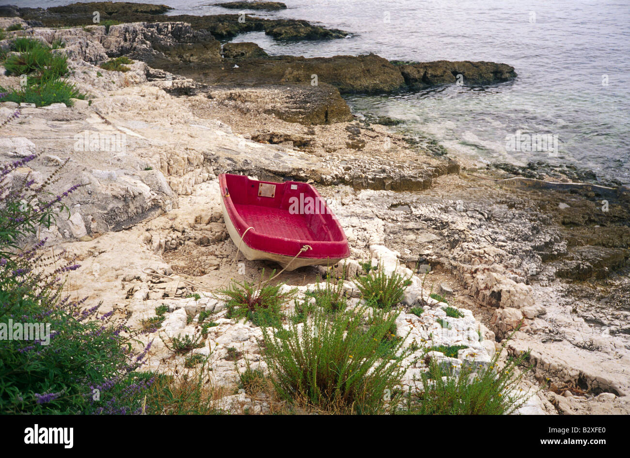 Red plastic boat on the rock near the sea Stock Photo - Alamy