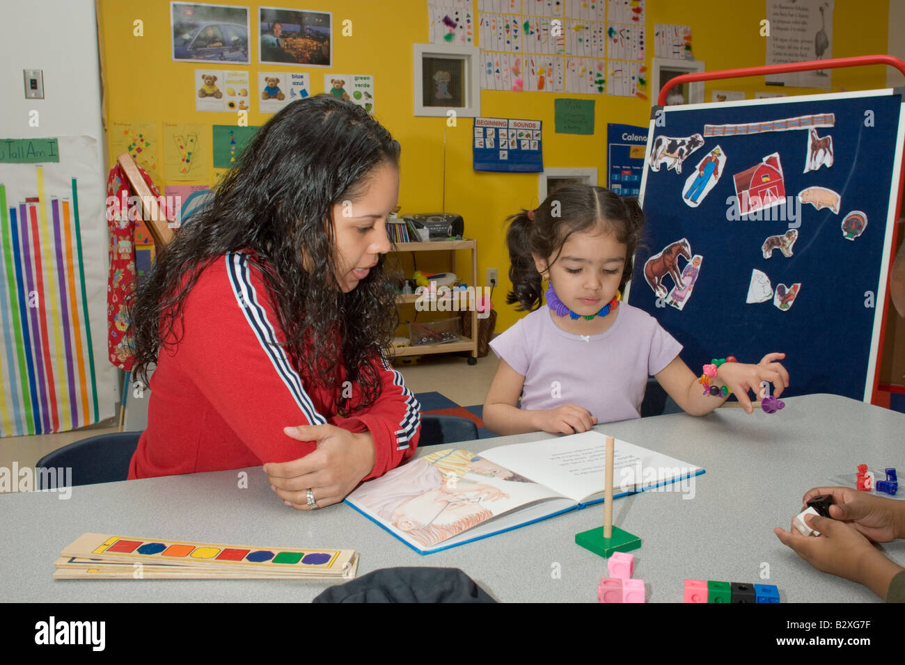 Preschool teacher reading a book with one of her students Stock Photo ...