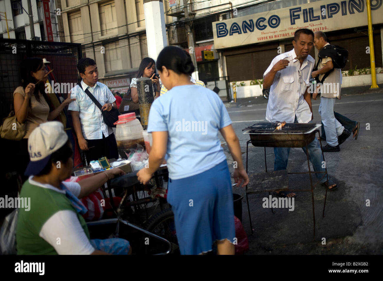 Filipinos stop for a quick snack at a street vendor's barbeque stand in ...