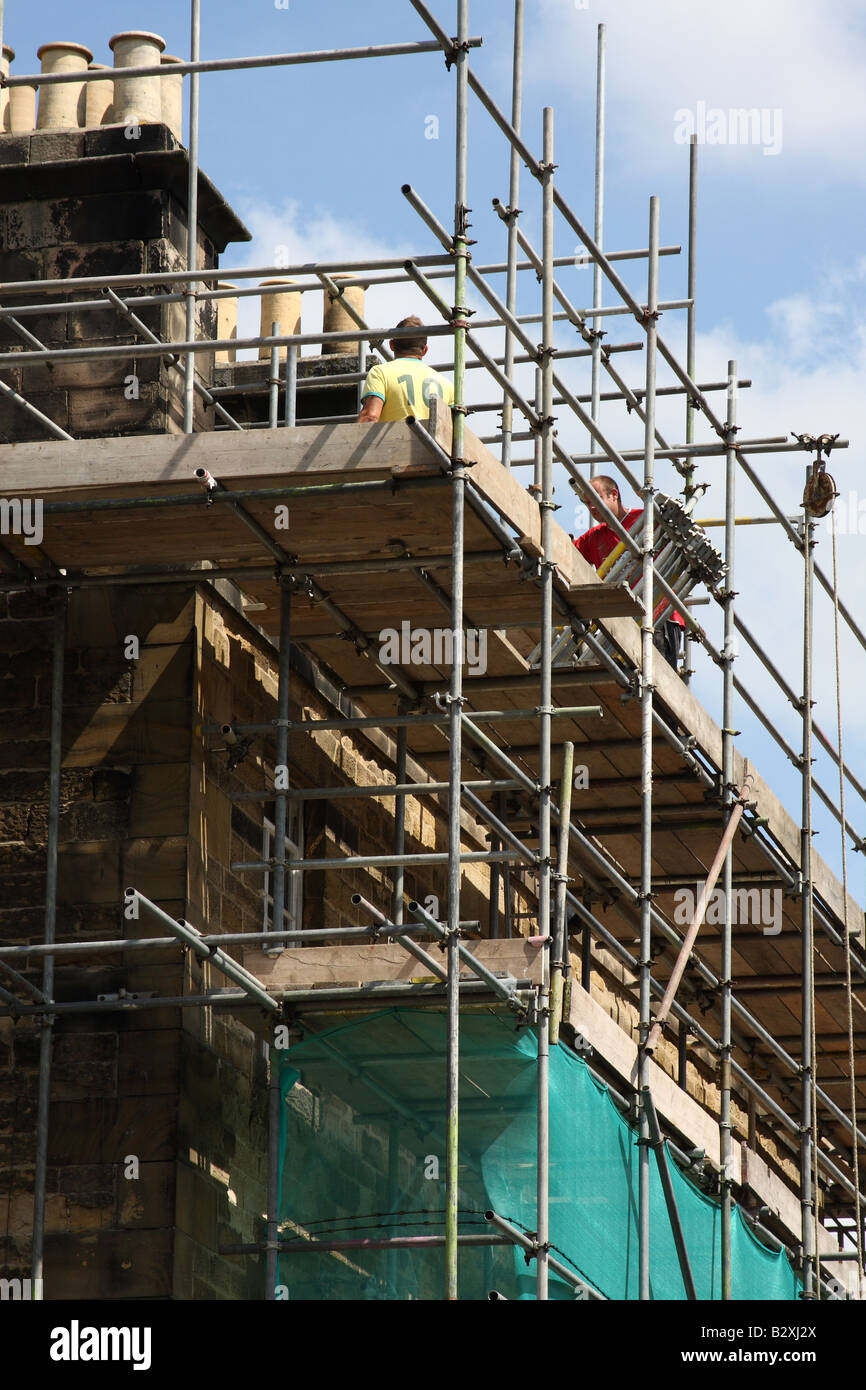 Construction workers working from scaffolding to repair a storm damaged ...