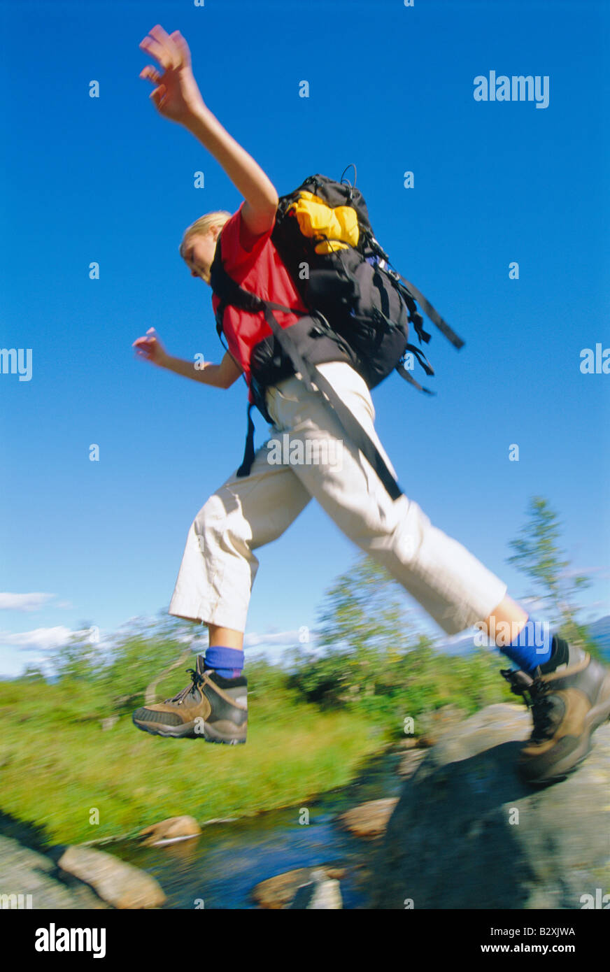Woman hiking outdoors jumping over stream (blur Stock Photo - Alamy